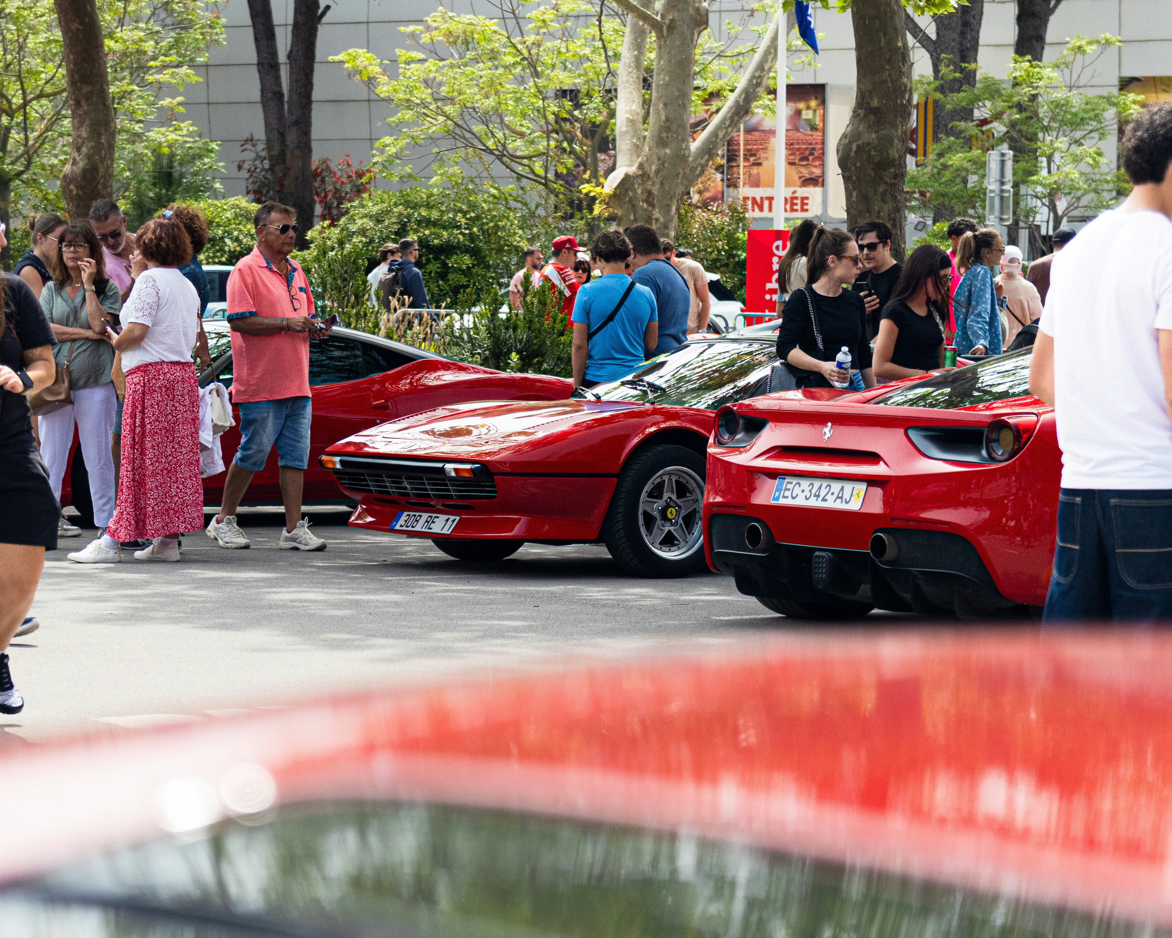 Red Supercars, City Crowd, and Afternoon Glare