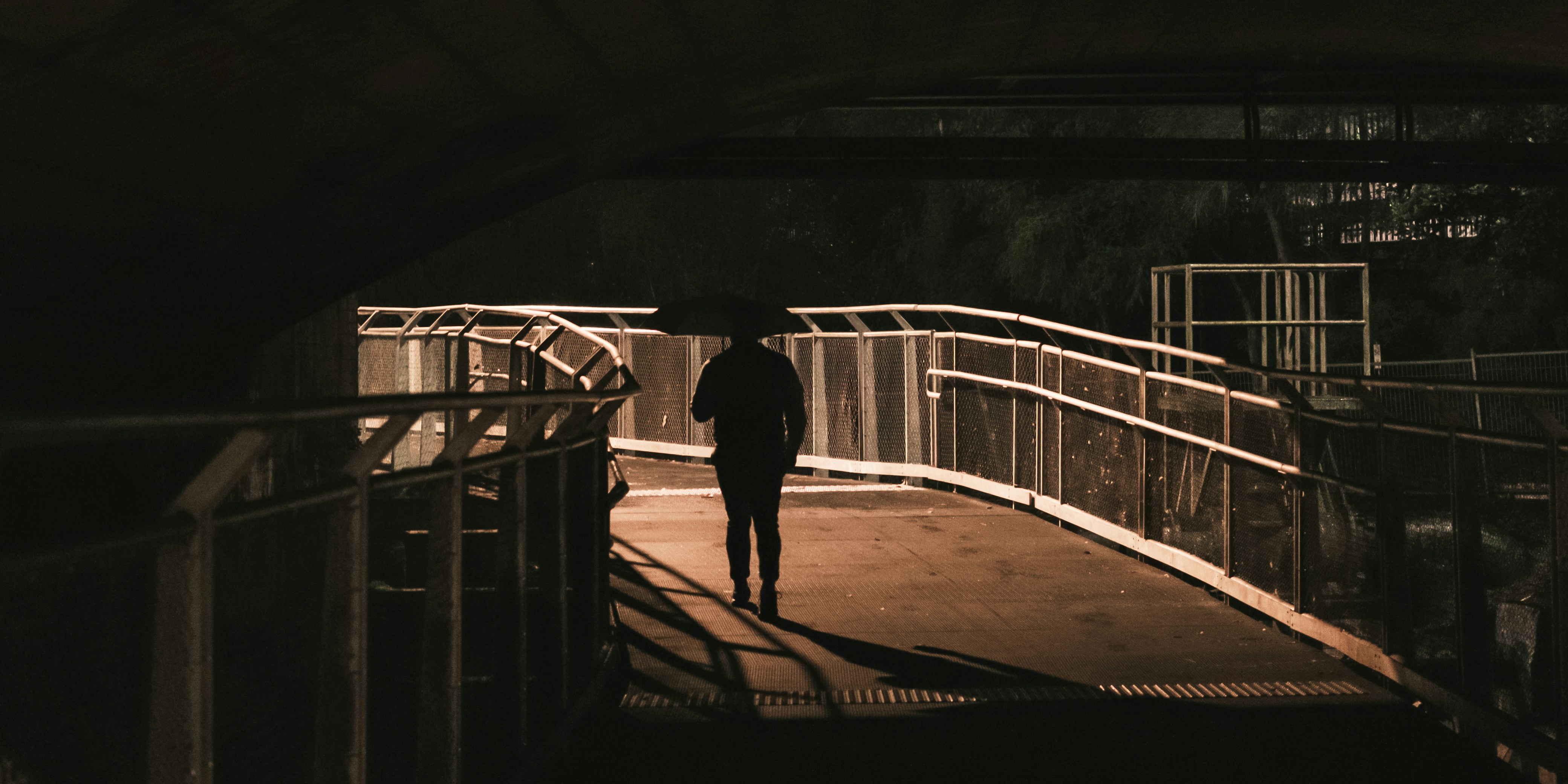 Midnight Crossing: A lone figure steps into the glow of a dimly lit bridge
