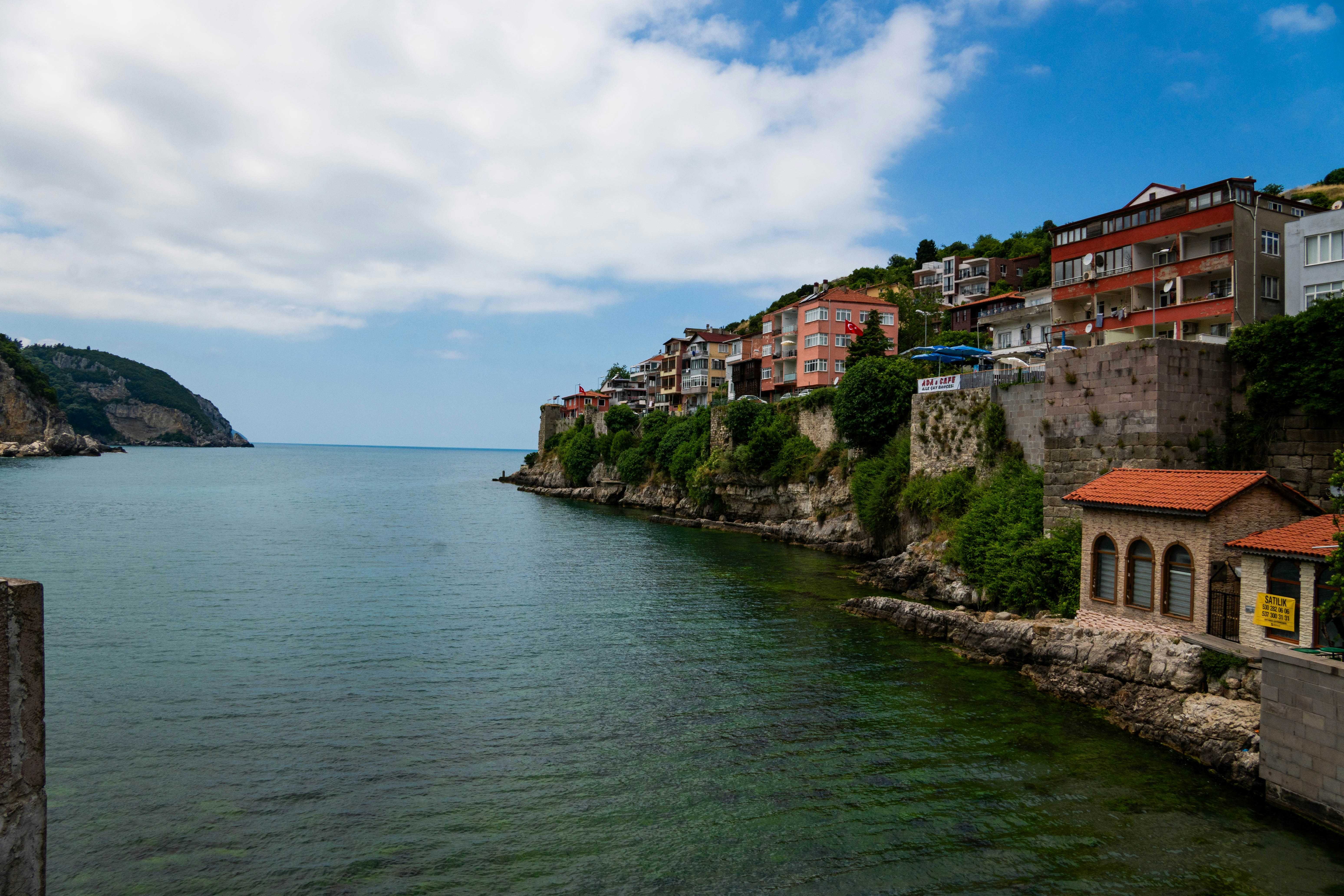 Harbor cliffs and colorful residences along a sunlit coastline
