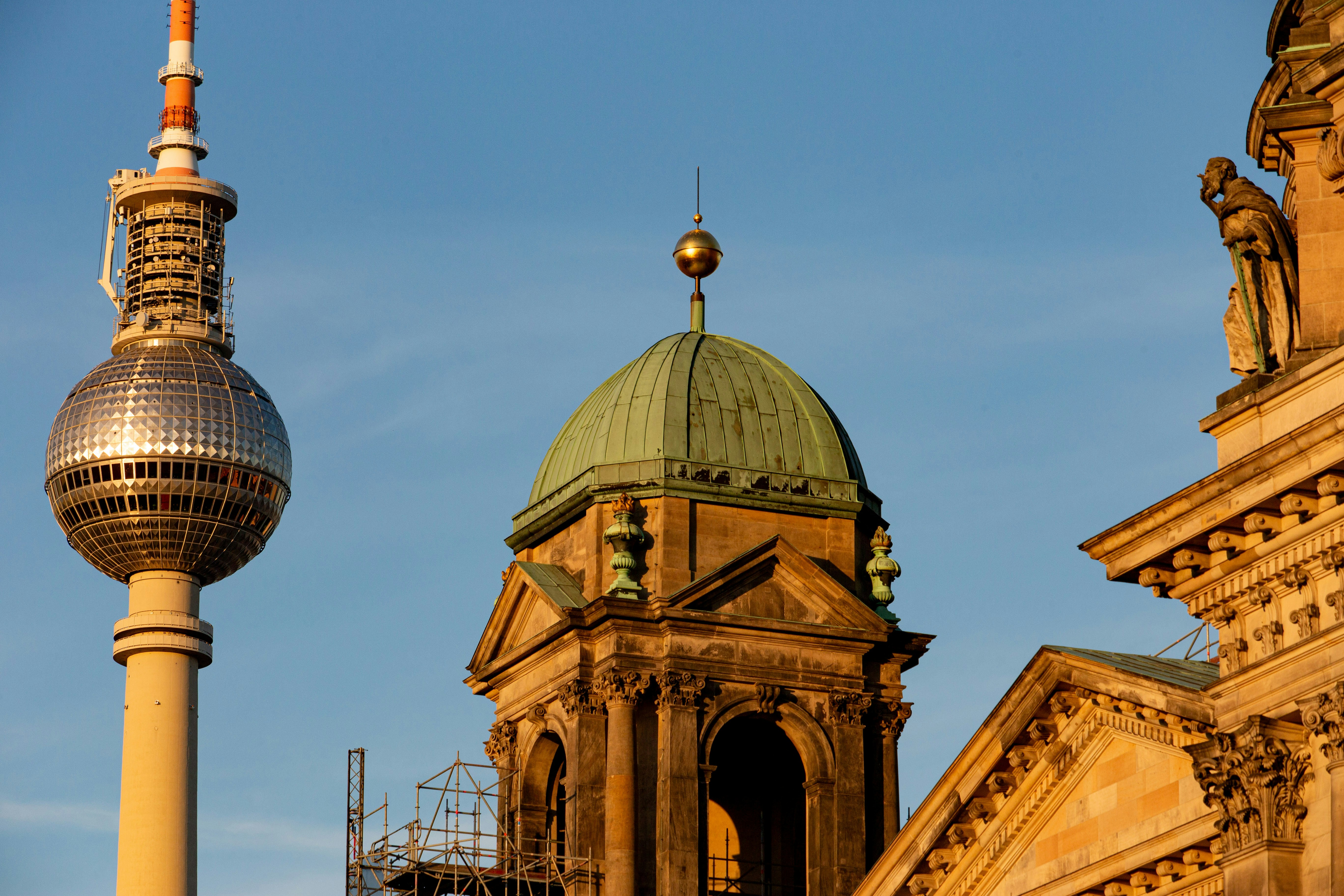 Rooftop domes and a tall metallic antenna rise against a blue sky, capturing architectural detail and city silhouette.