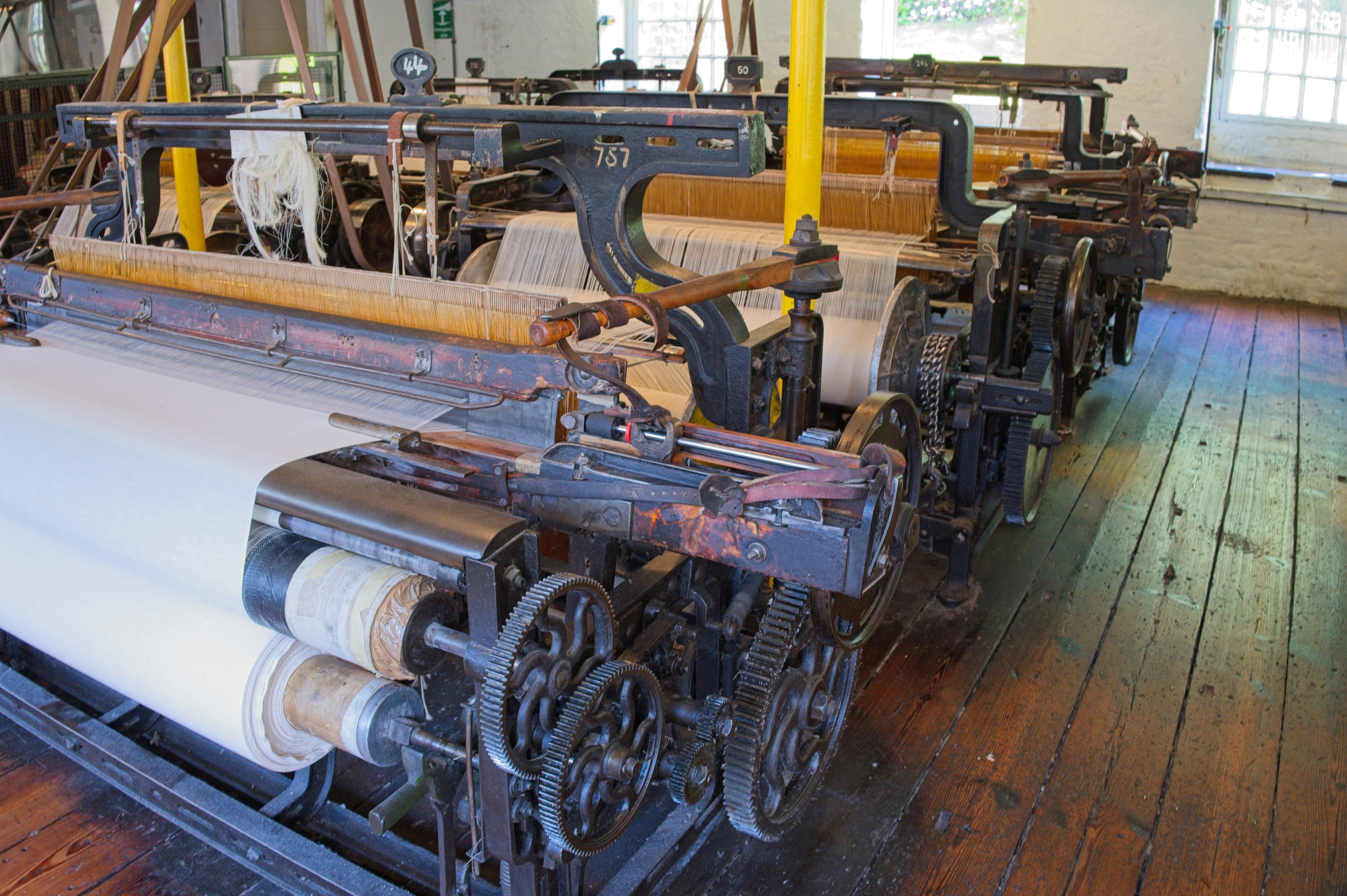 Industrial Looms: A Row of Vintage Weaving Machines Resting in a Wooden Workshop