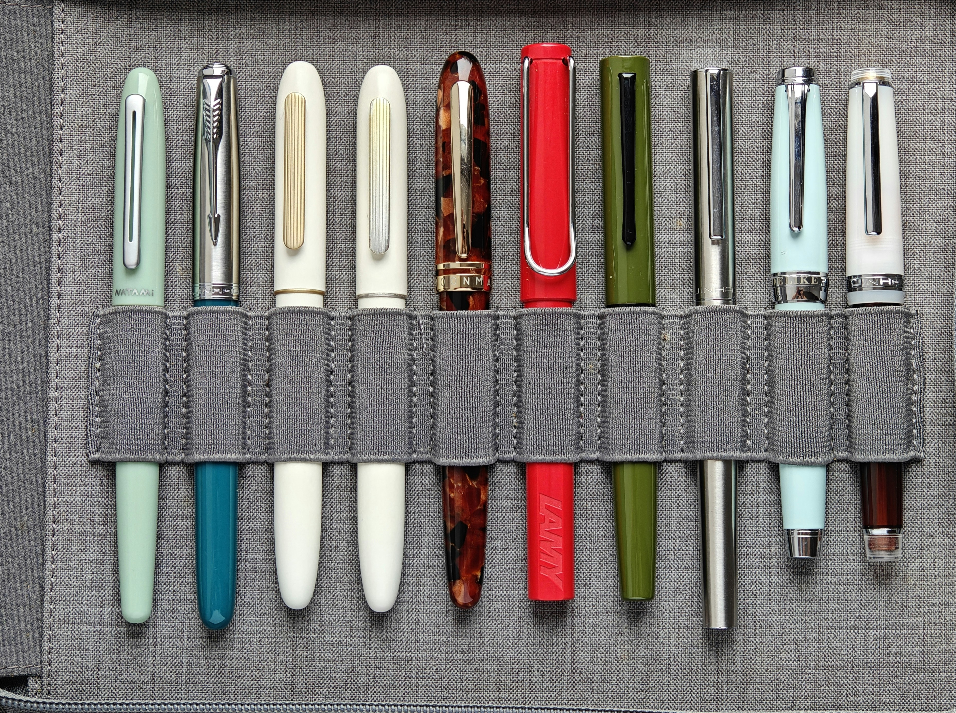 Row of colorful fountain pens in a fabric organizer