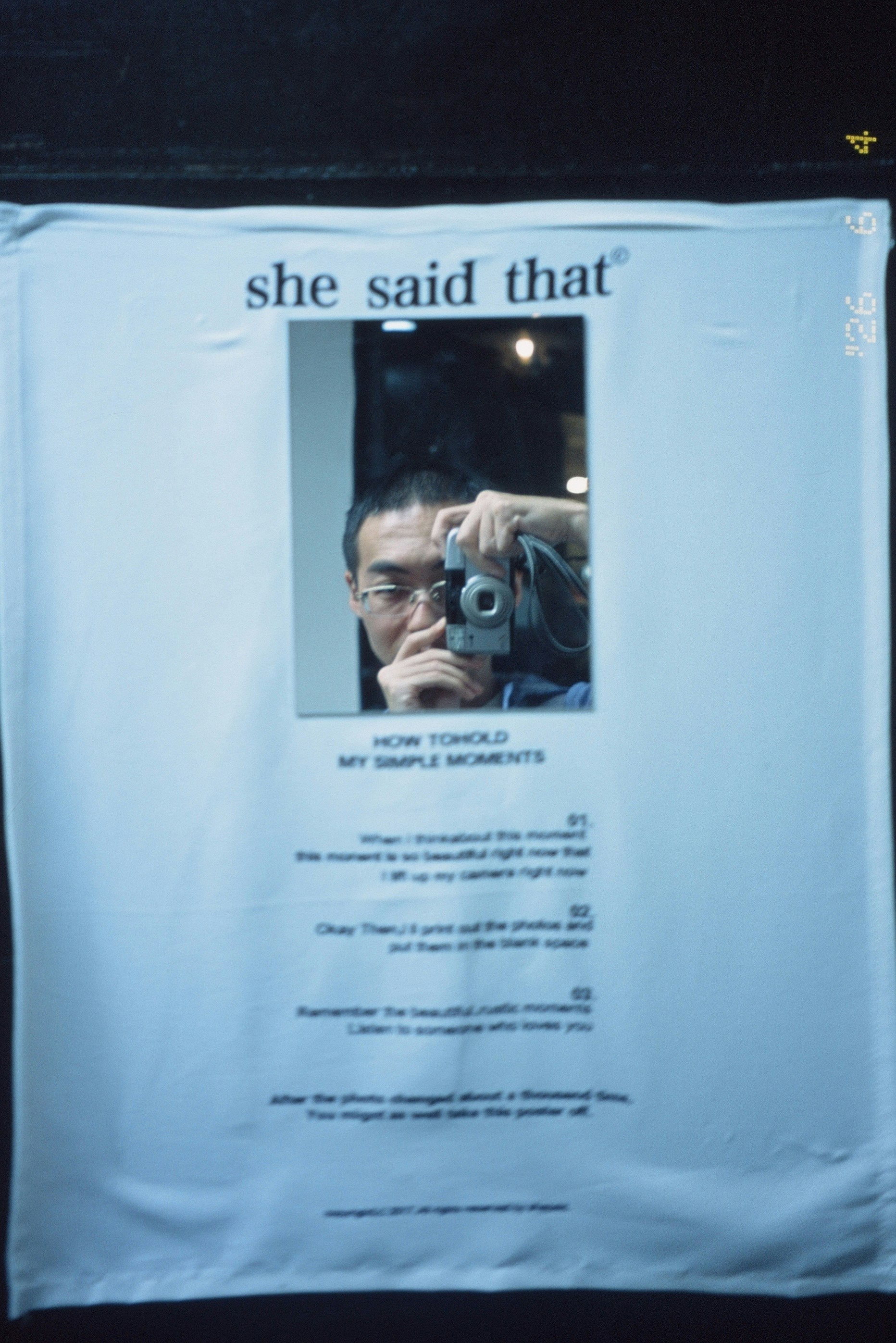 Self-portrait in a mirror within a poster cover: a photographer peeks through a small central window