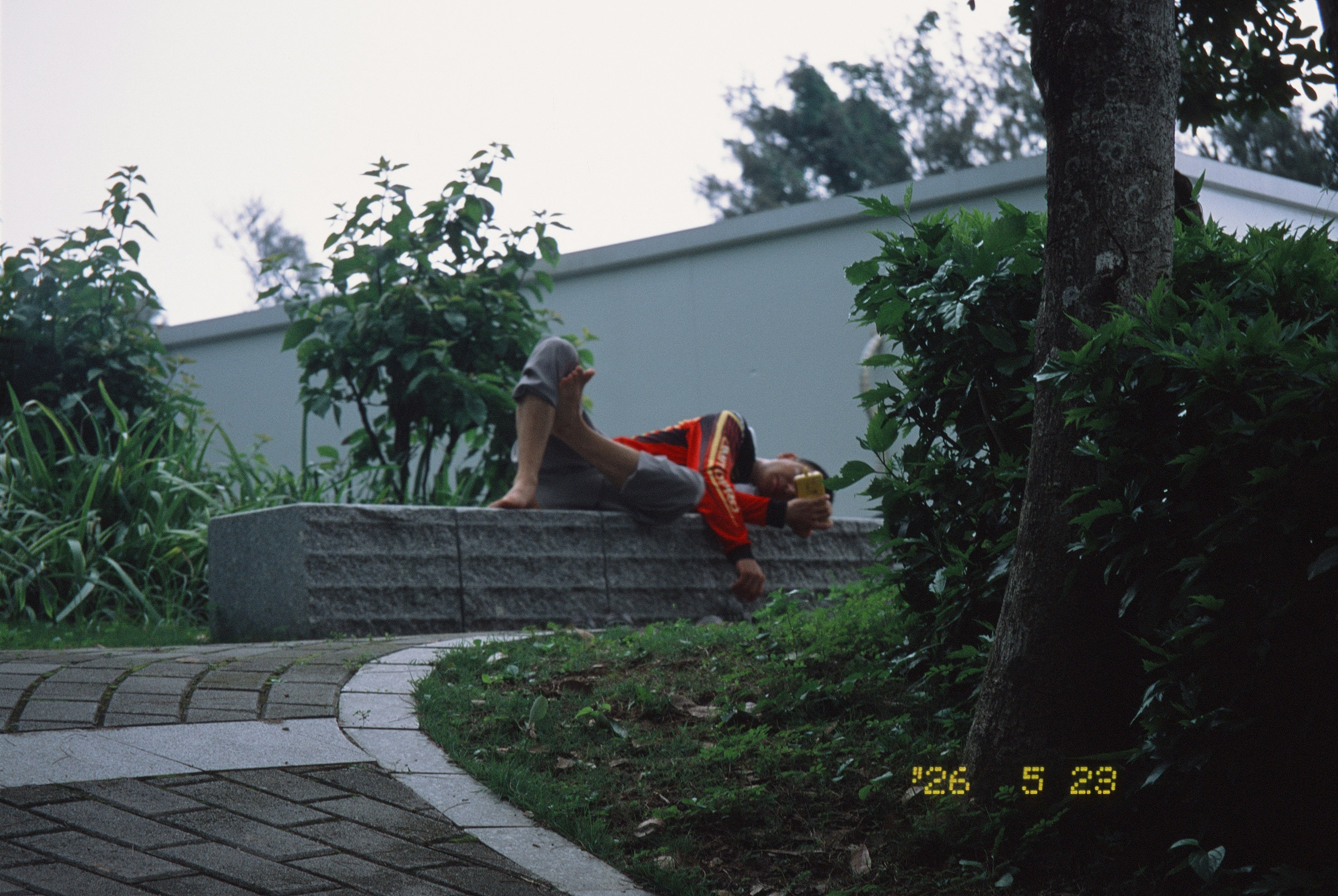 Child on a Curved Stone Bench Reaching for Ground-Level Play