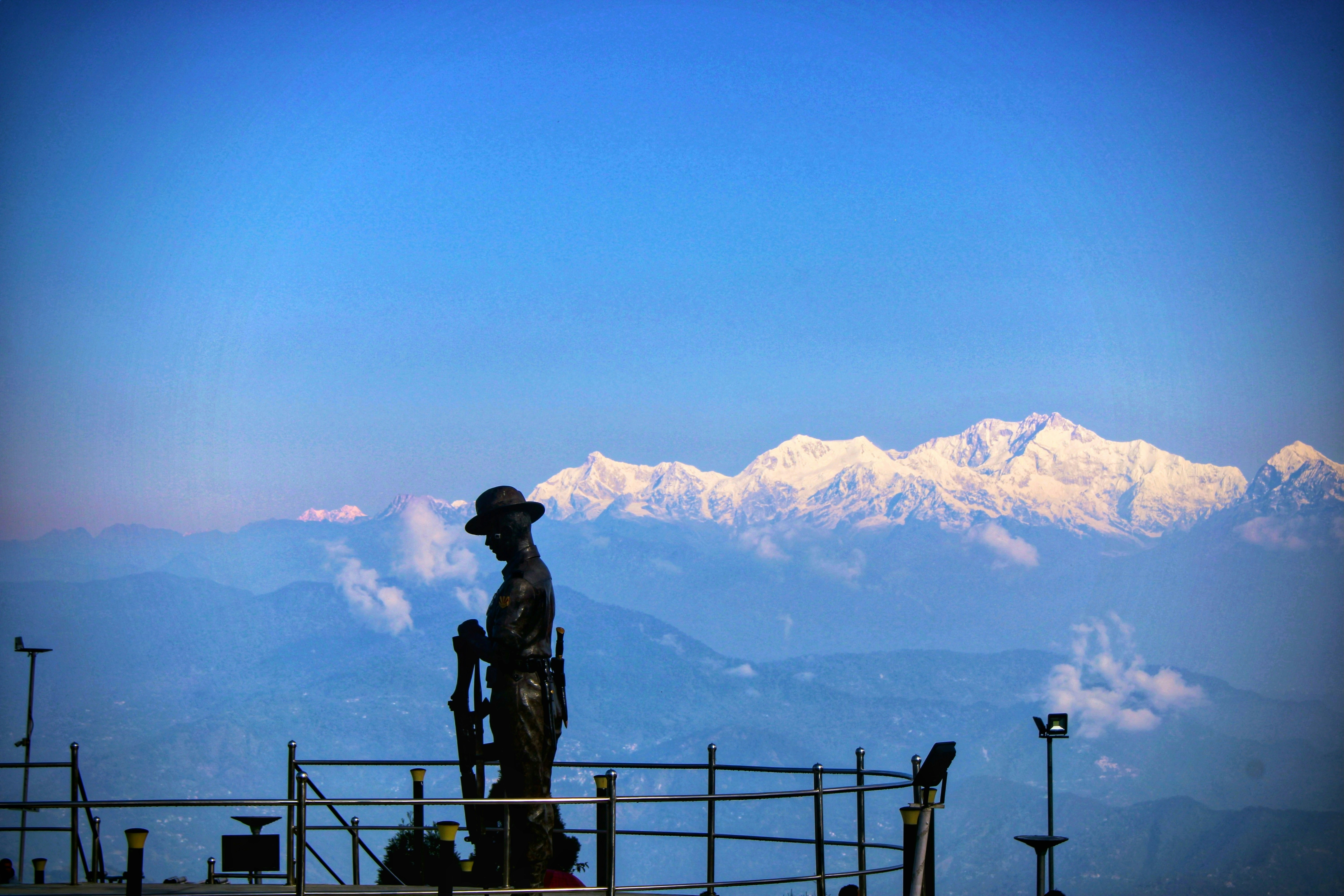 Silhouette on the Skyline: A Ledge View Toward Snow-Capped Peaks