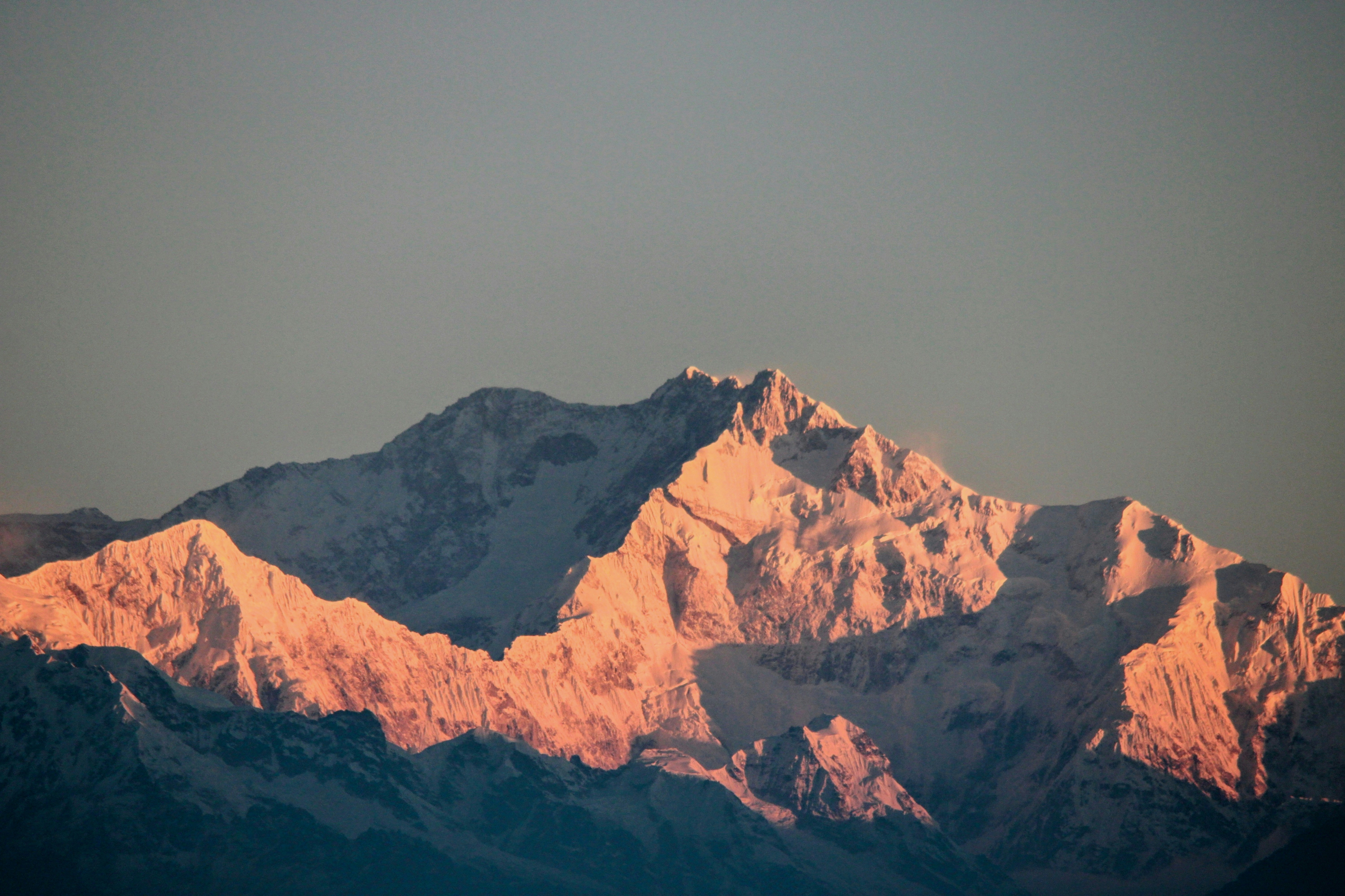 Sunlit Apex: The Warm Pale Dawn over Craggy Peaks