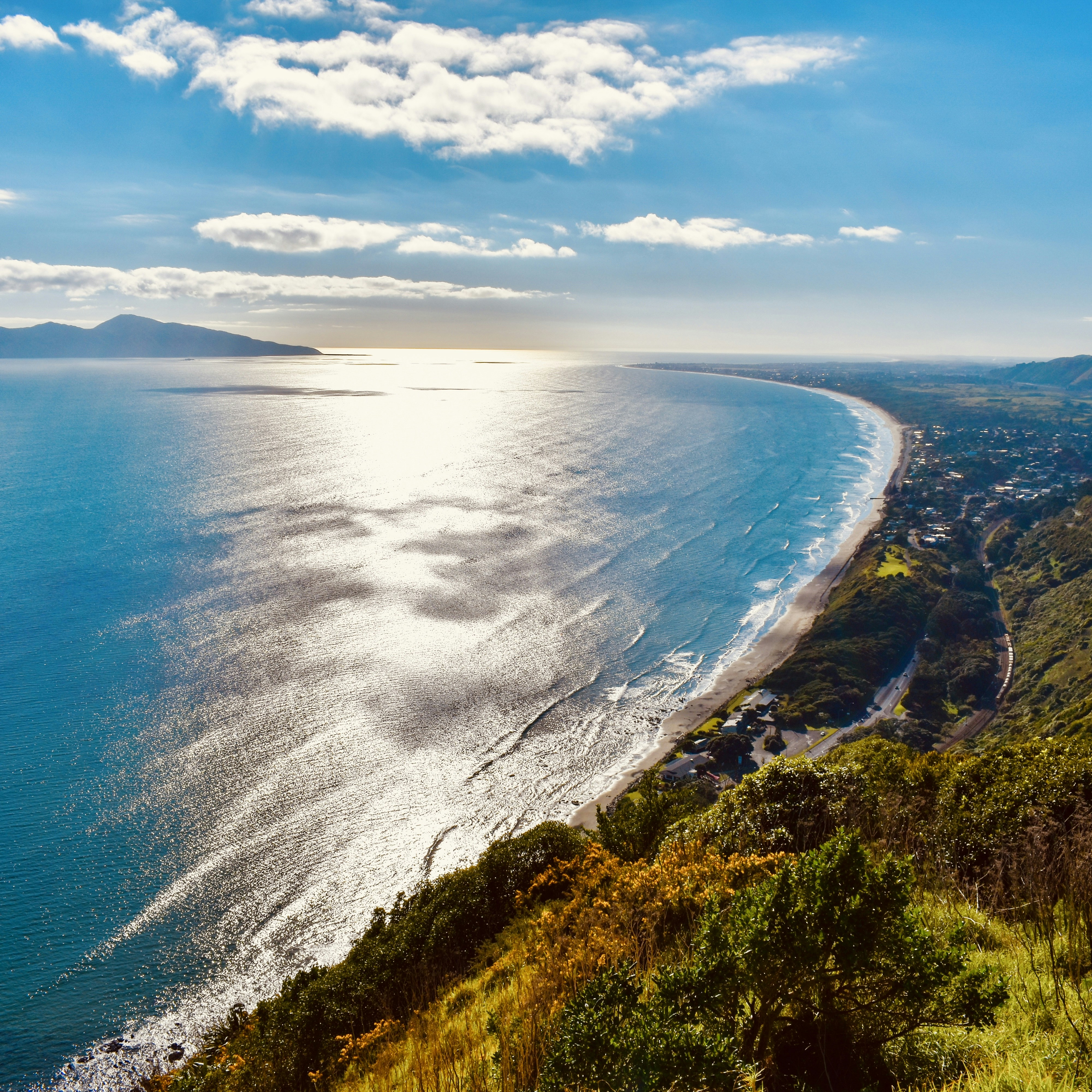 Sunlit Coastline: Aerial Vista Over Curving Bay and Cliffside Town