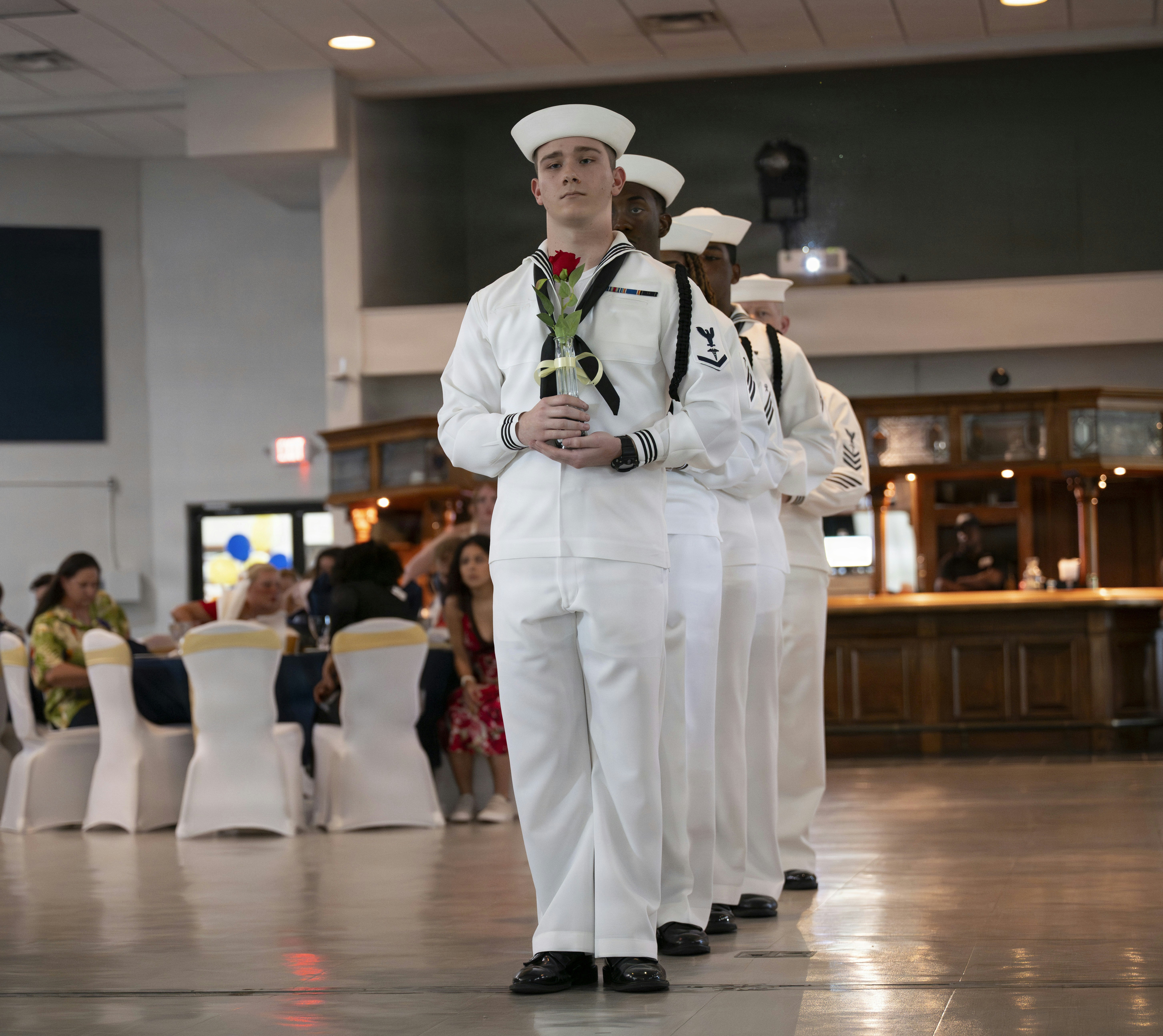Silent Honor: A Line of Sailors Holds a Rose in a Quiet Ceremony
