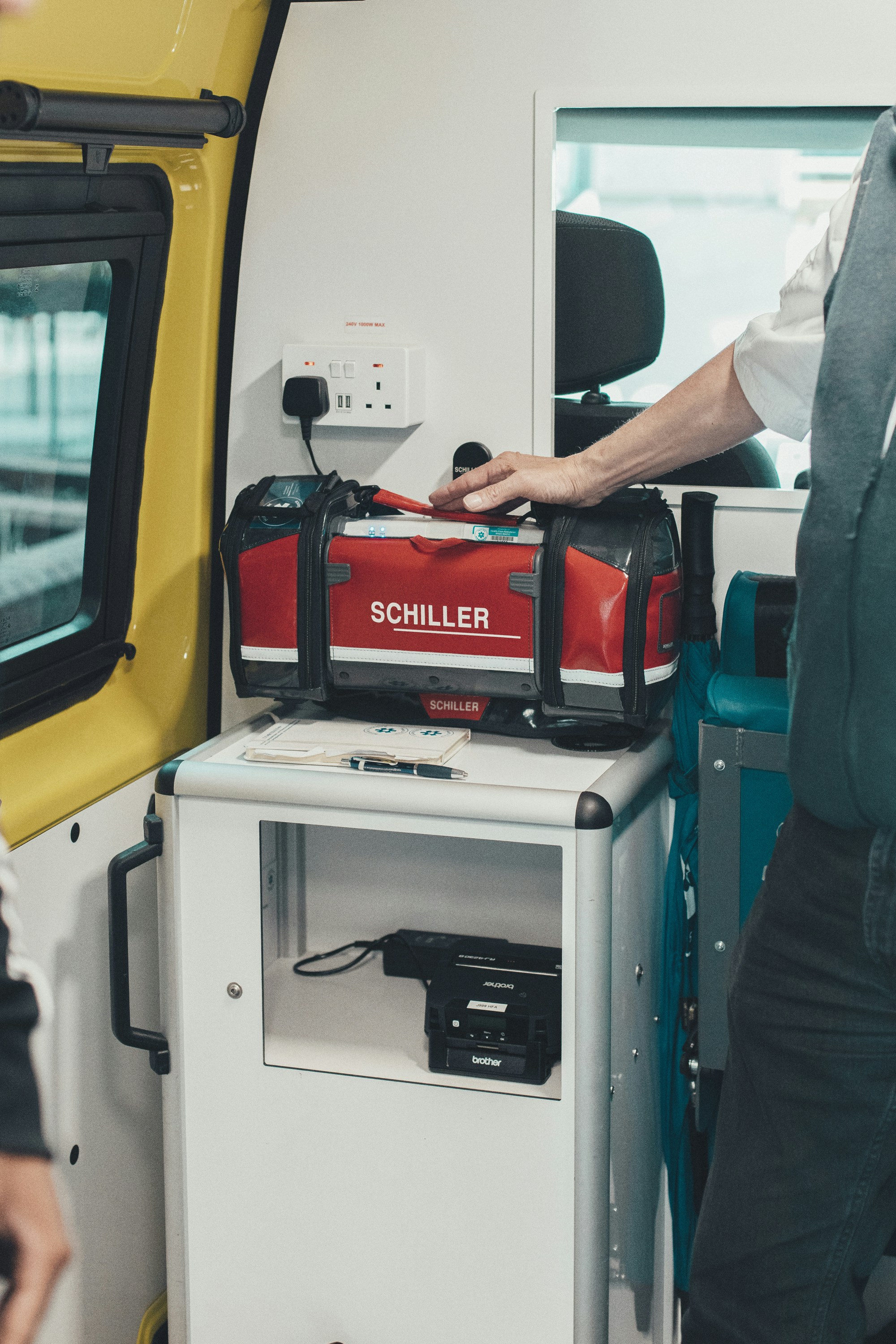 Red medical bag anchored on a white cabinet inside a vehicle