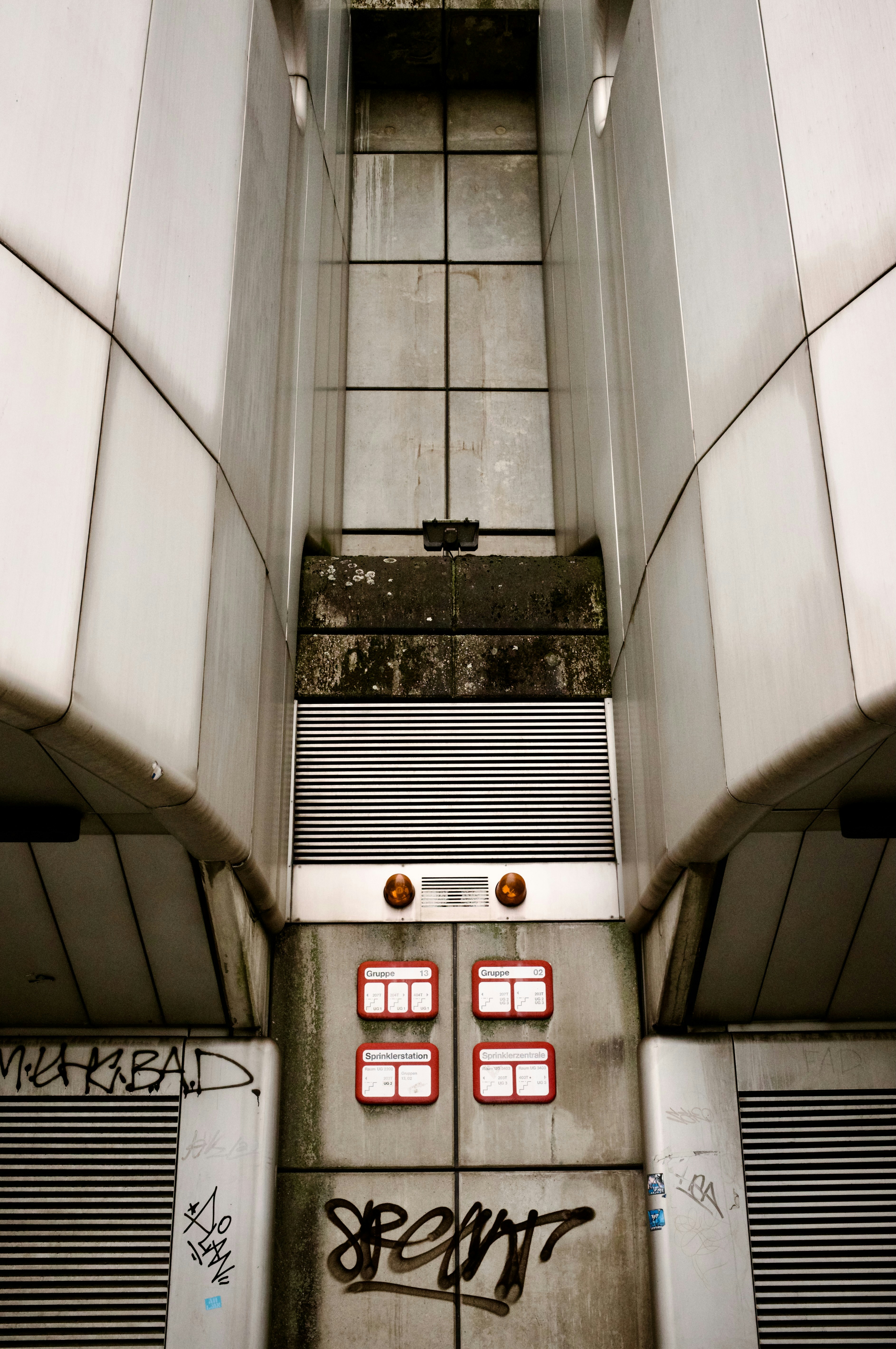 Vantage of Concrete Towers: An Urban Shaft Framed by Graffiti and Industrial Lines