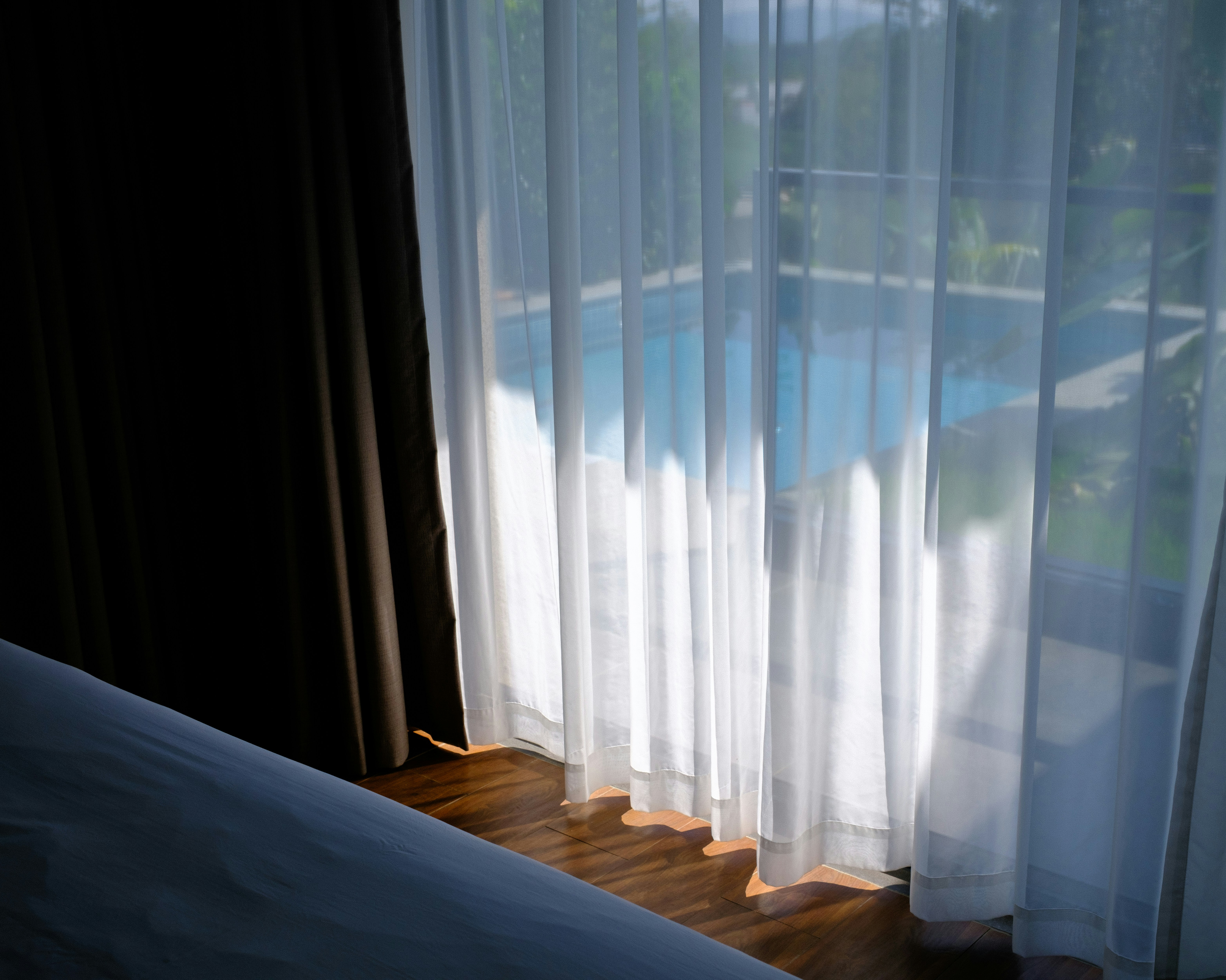 Sunlit Sheer Curtain Over Poolside View