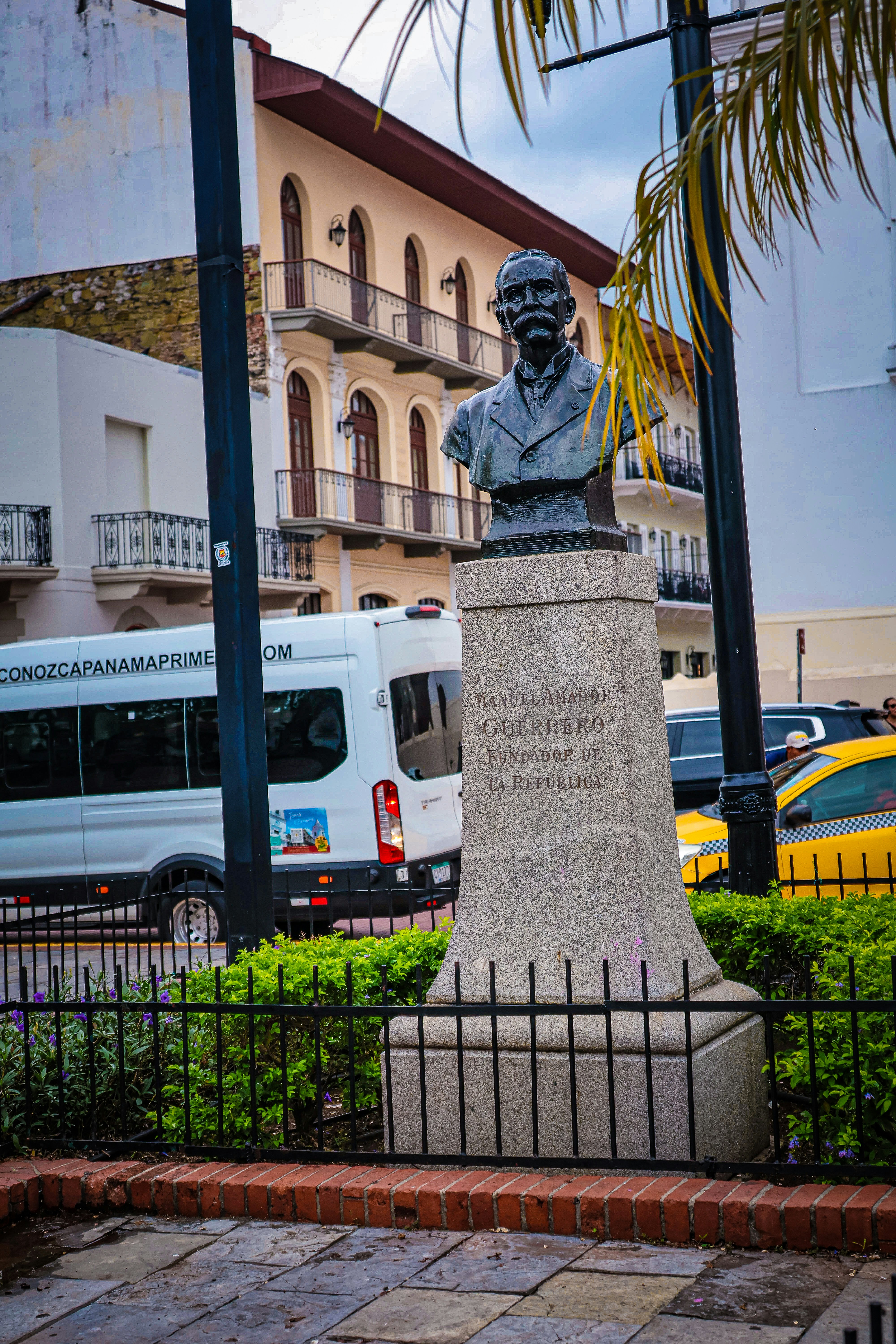 Bust of José Martí in a sunlit plaza framed by colonial balconies
