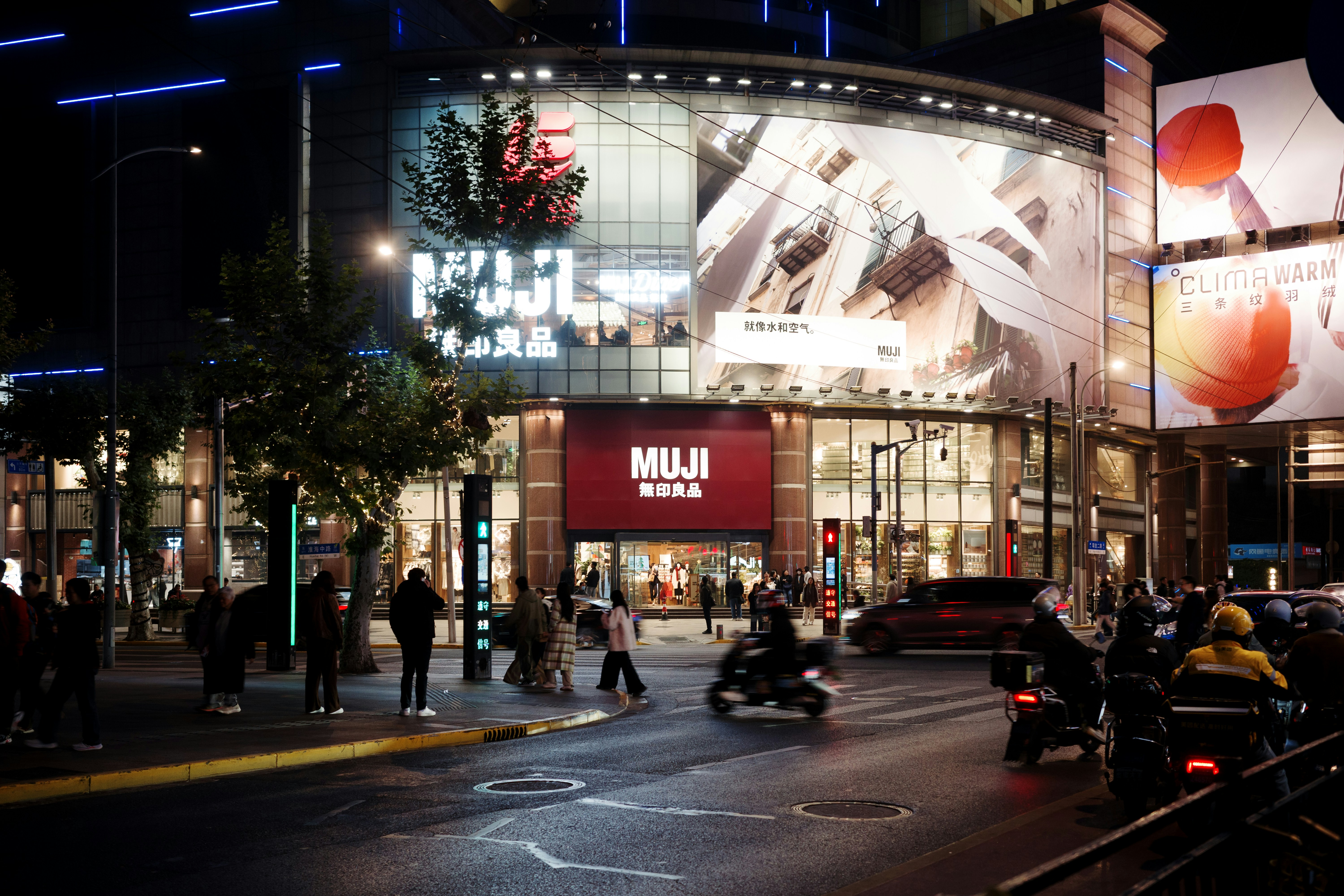 Muji Store Amid Nightlife Buzz on a Bustling City Street