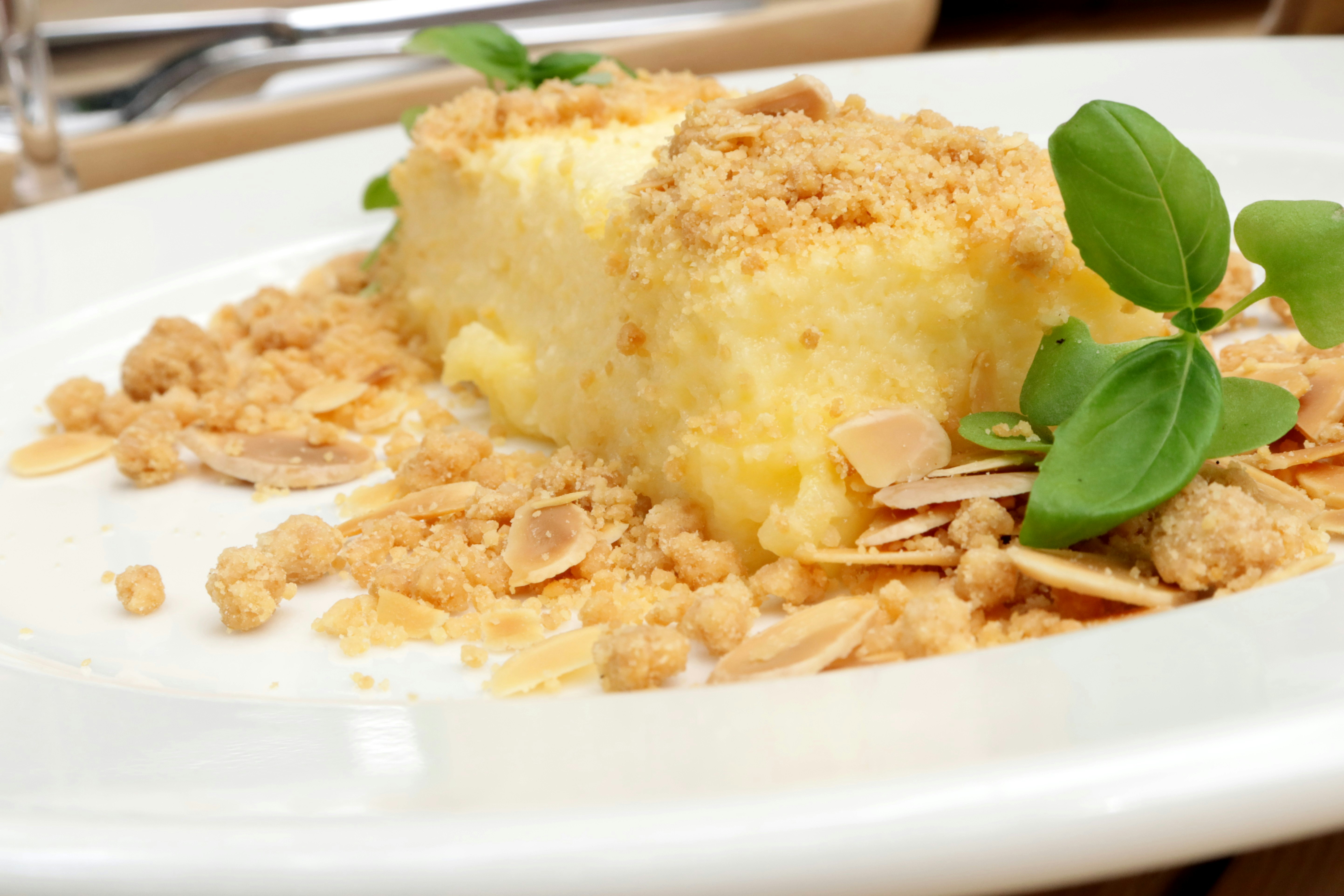 Citrus-vanilla cheesecake slice nestled in almond crumble on a glossy plate