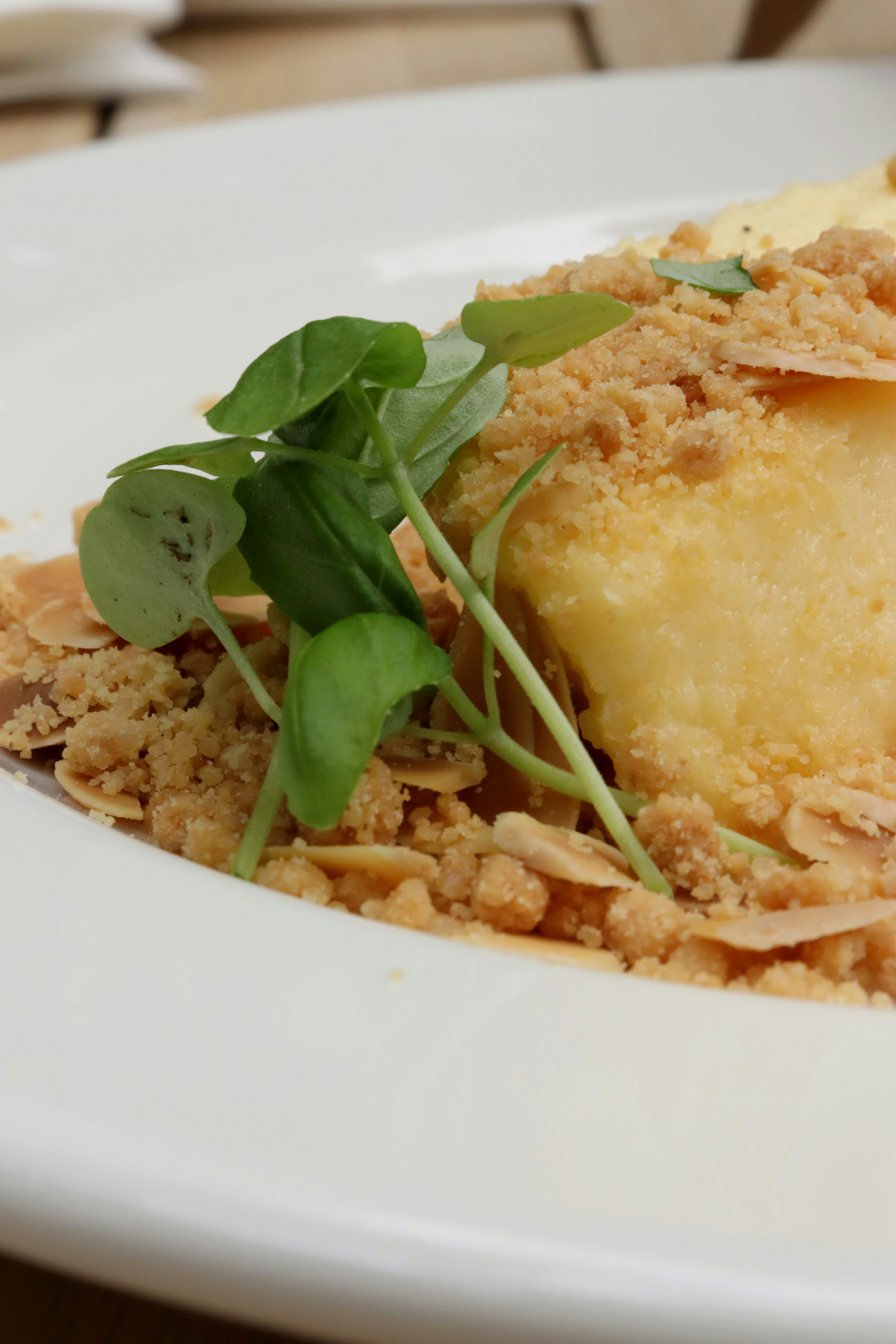Crisped Tine Crumble Cradling a Green Garnish on a Creamy Plate