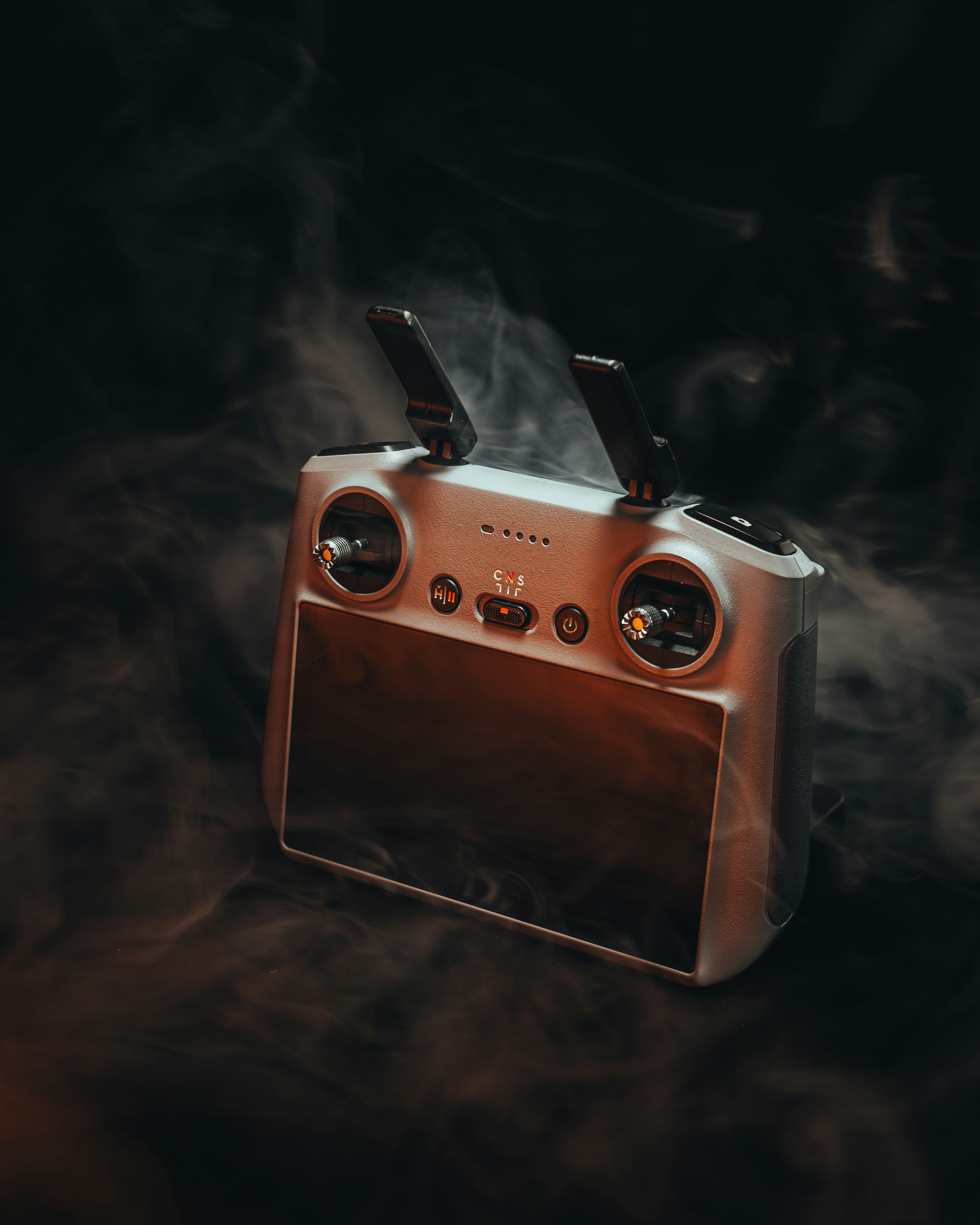 A retro-styled handheld camera sits amid swirling smoke against a dark backdrop, highlighting its metallic contours and exposed dials.