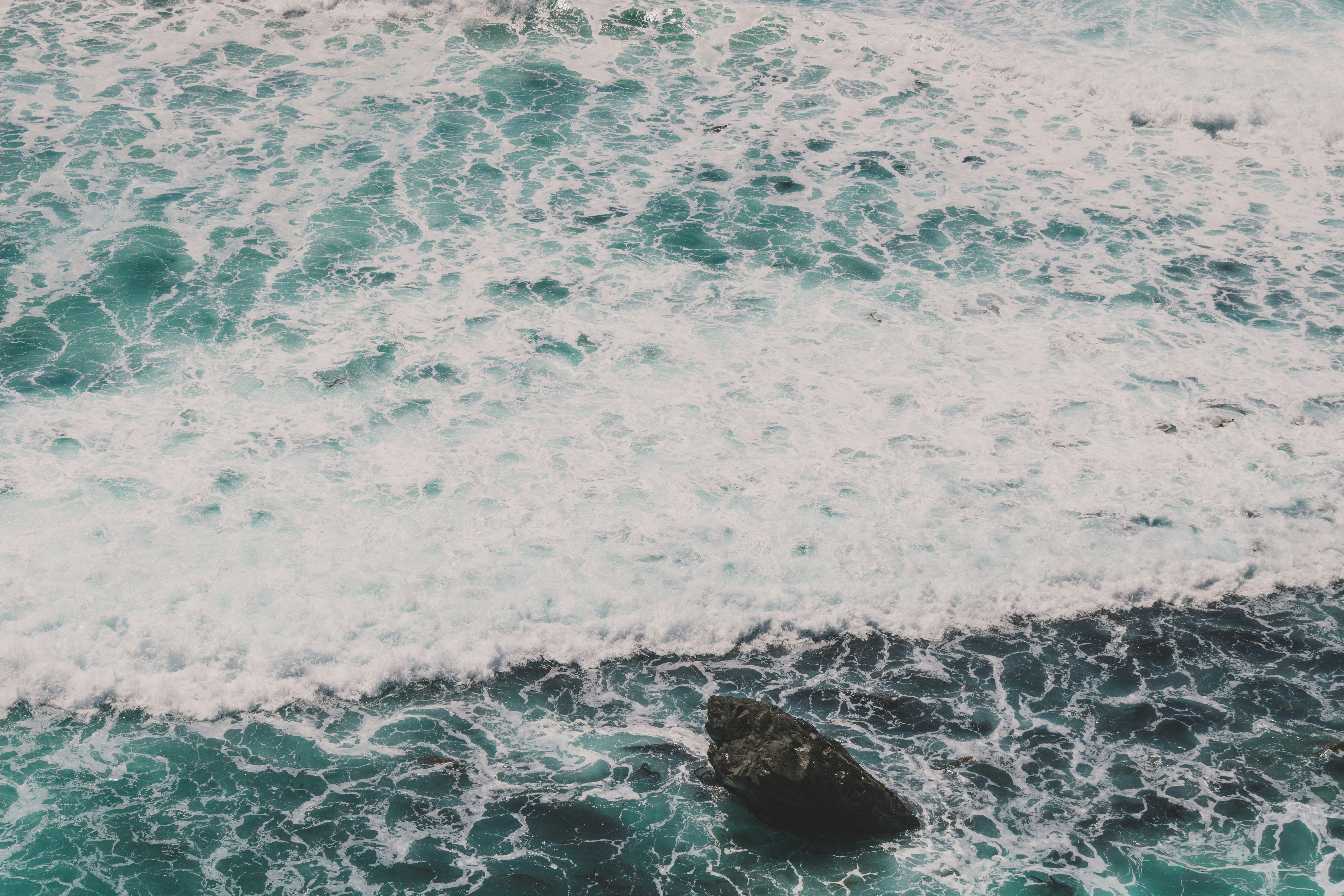 Turbulent Crest: A Lone Rock Anchored in The Sea's White Frill