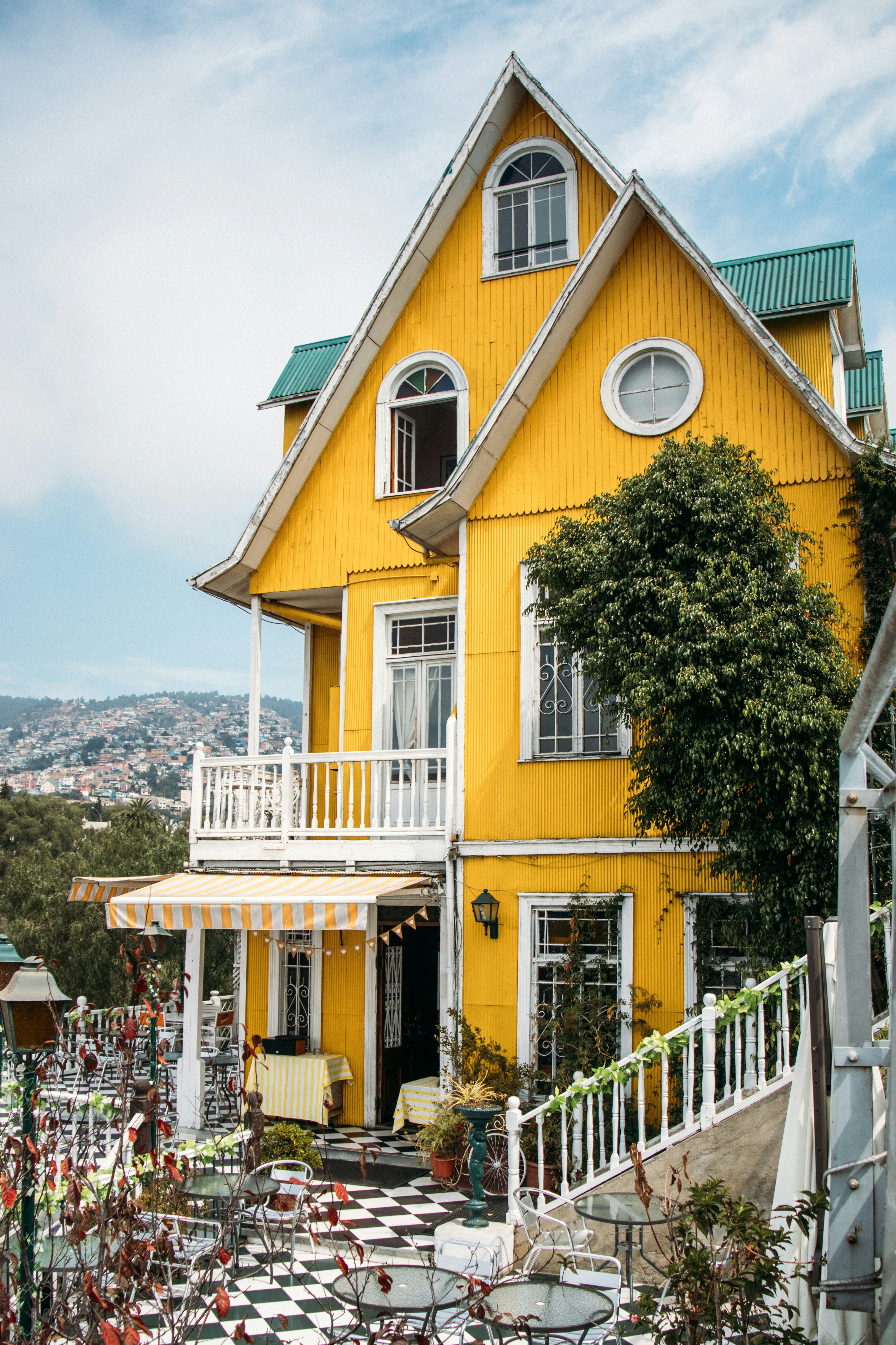 Sunlit Yellow House with White Trim in a Lively Courtyard