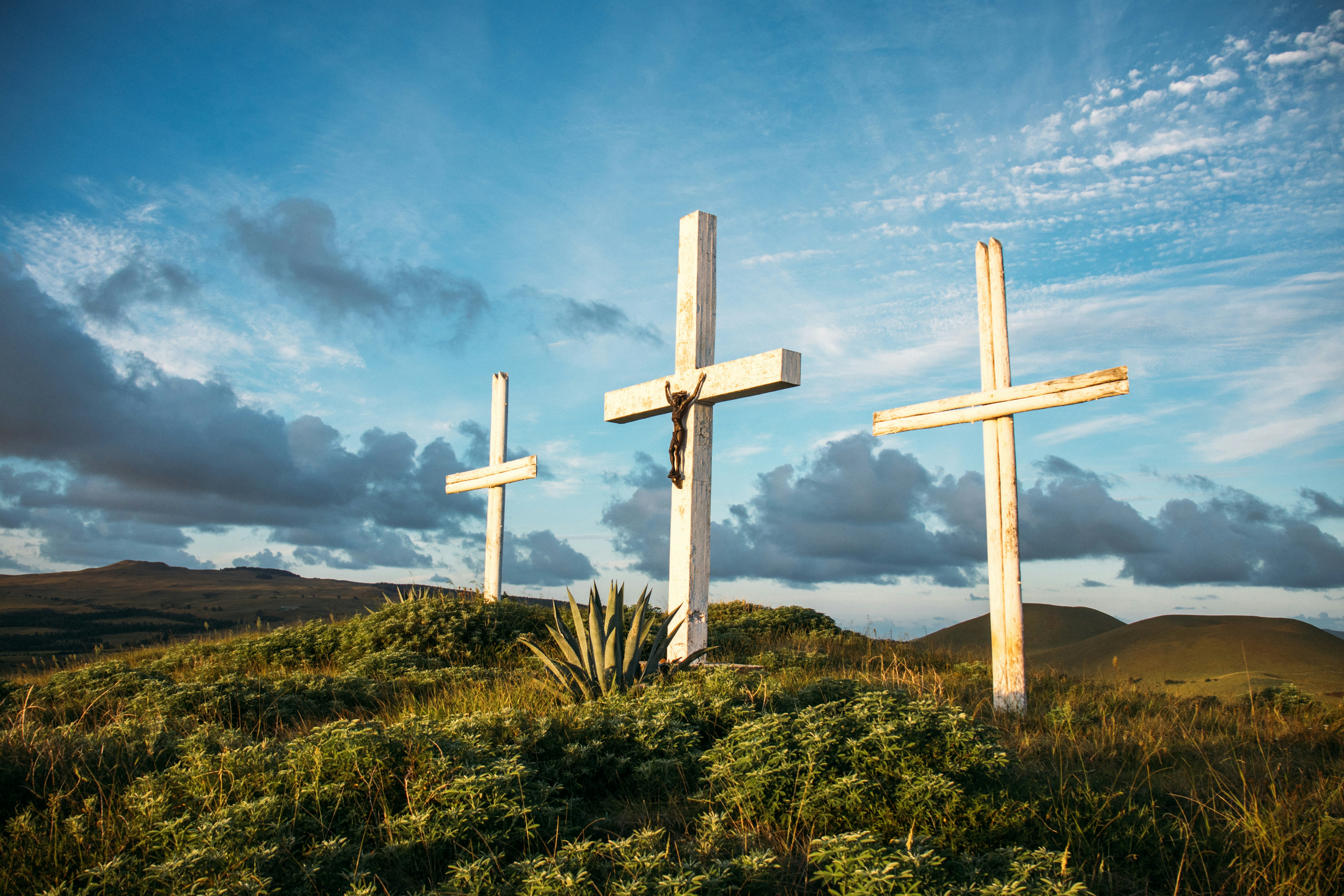 Three Weathered Crosses atop a grassy hillside at golden hour
