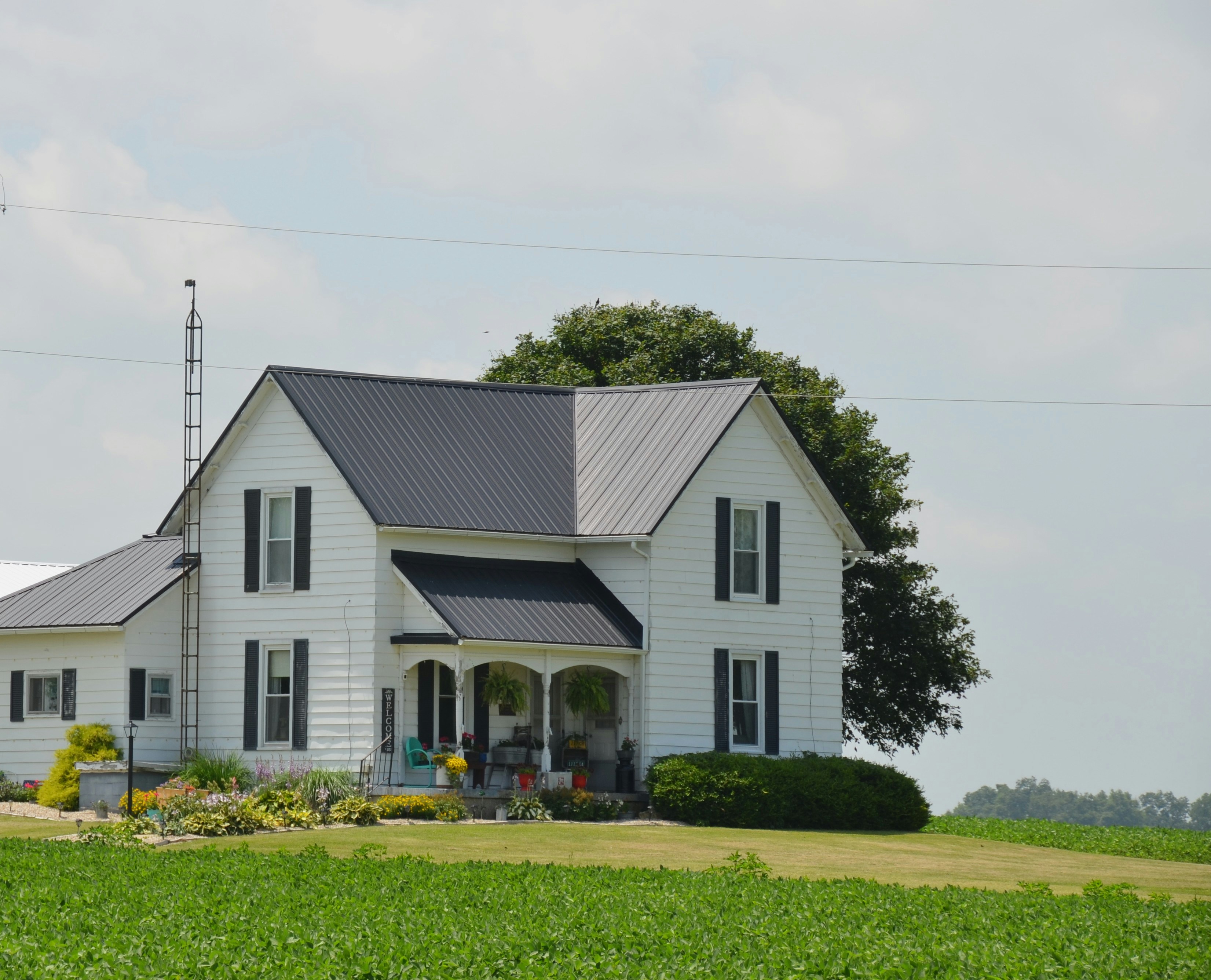 White farmhouse under a blue sky with well-kept front yard