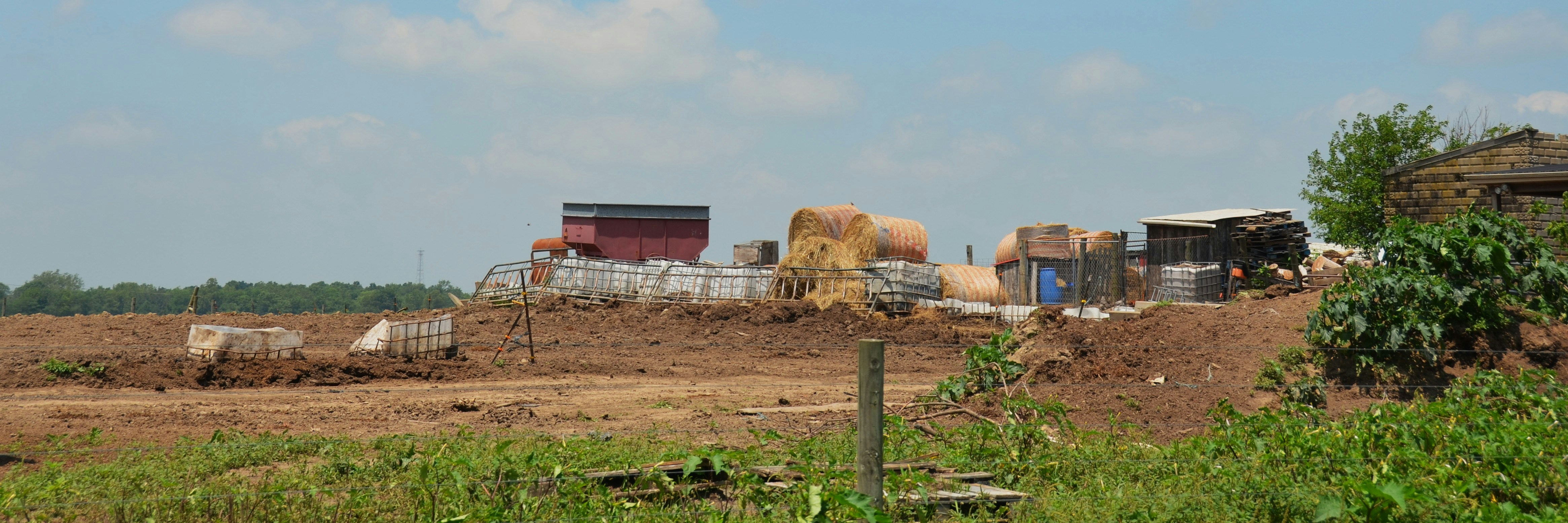 Harvestyard Silhouette: Hay Bales and Shelters on a Distant Plain