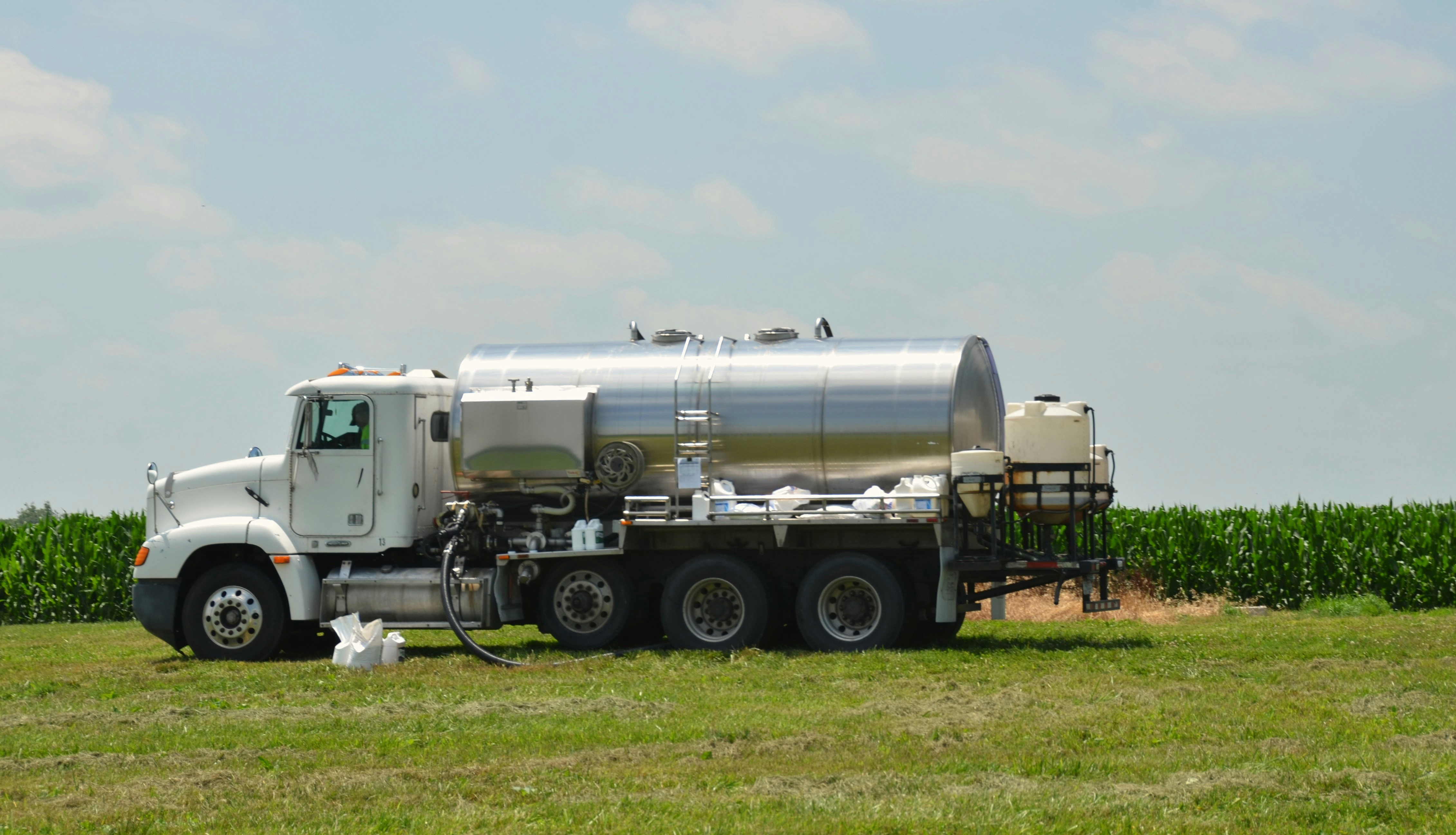 Metallic tanker at the edge of a cornfield under a bright sky