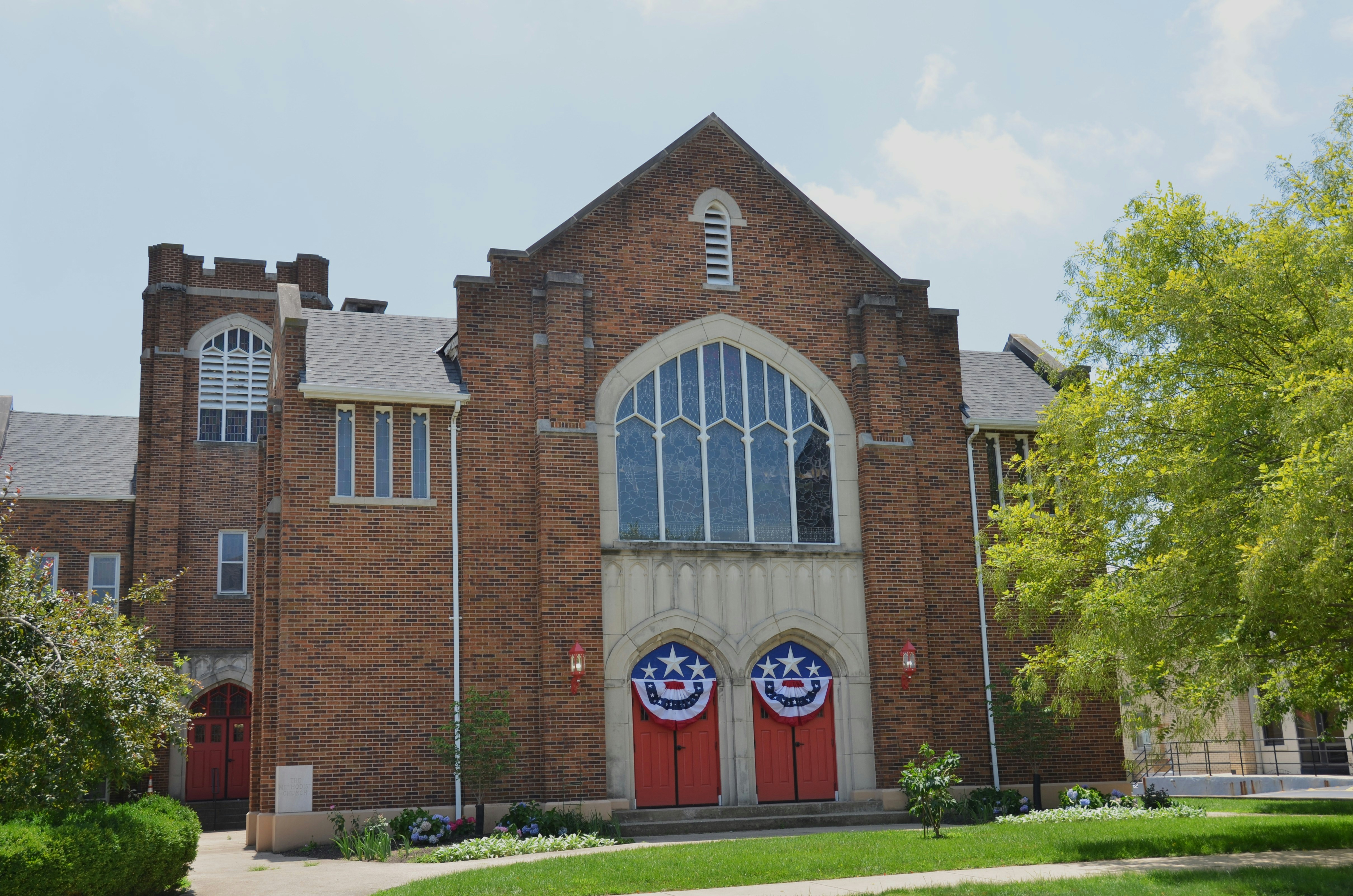 Brick Gothic Revival Facade: Red doors, star-spangled banners, and a sunlit campus entrance