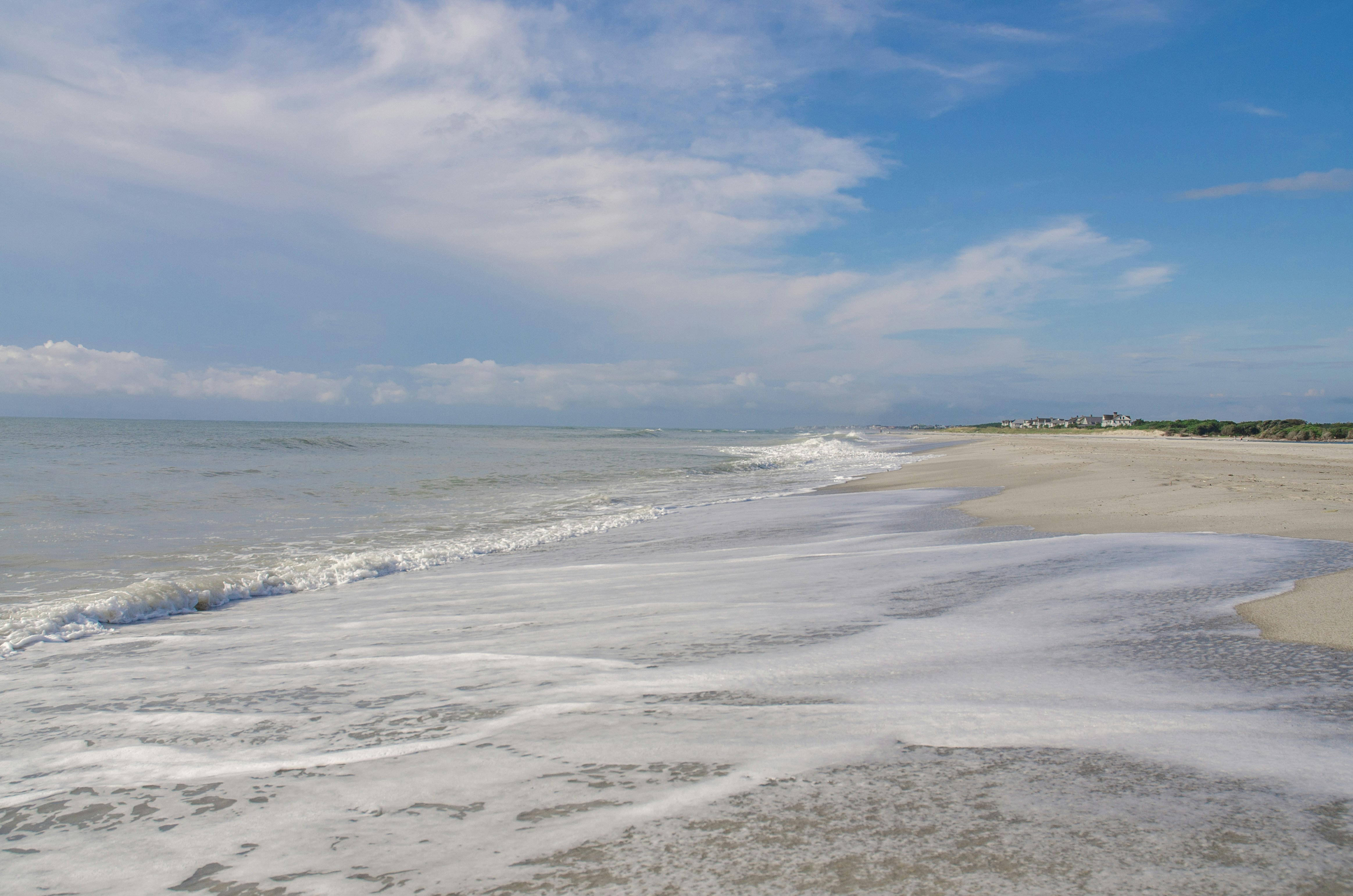 Coastal Quiet: Wet Sand, Foam, and Distant Dunes under a Wide Sky
