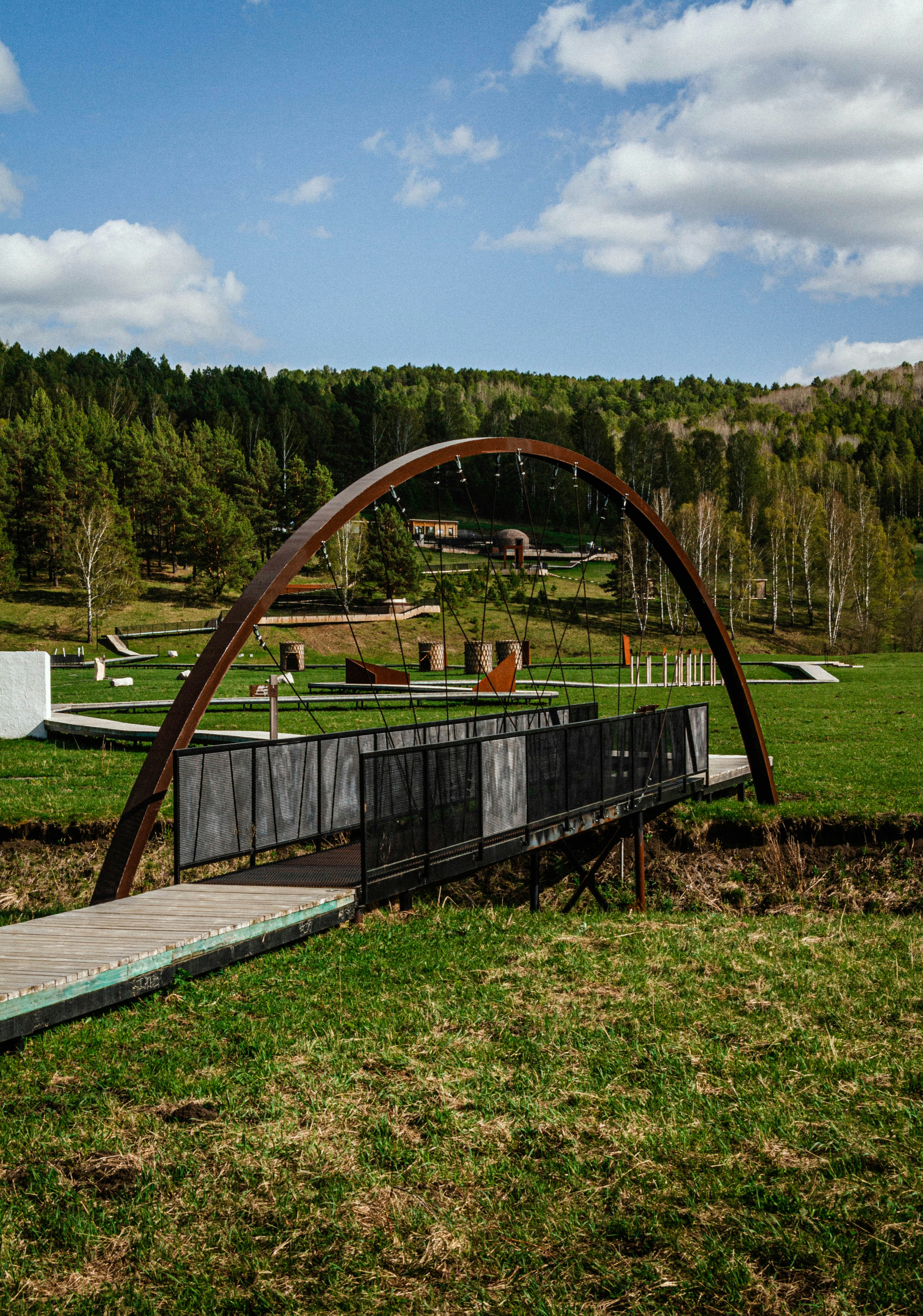Arching Bridge Over Green Field in a Quiet Park