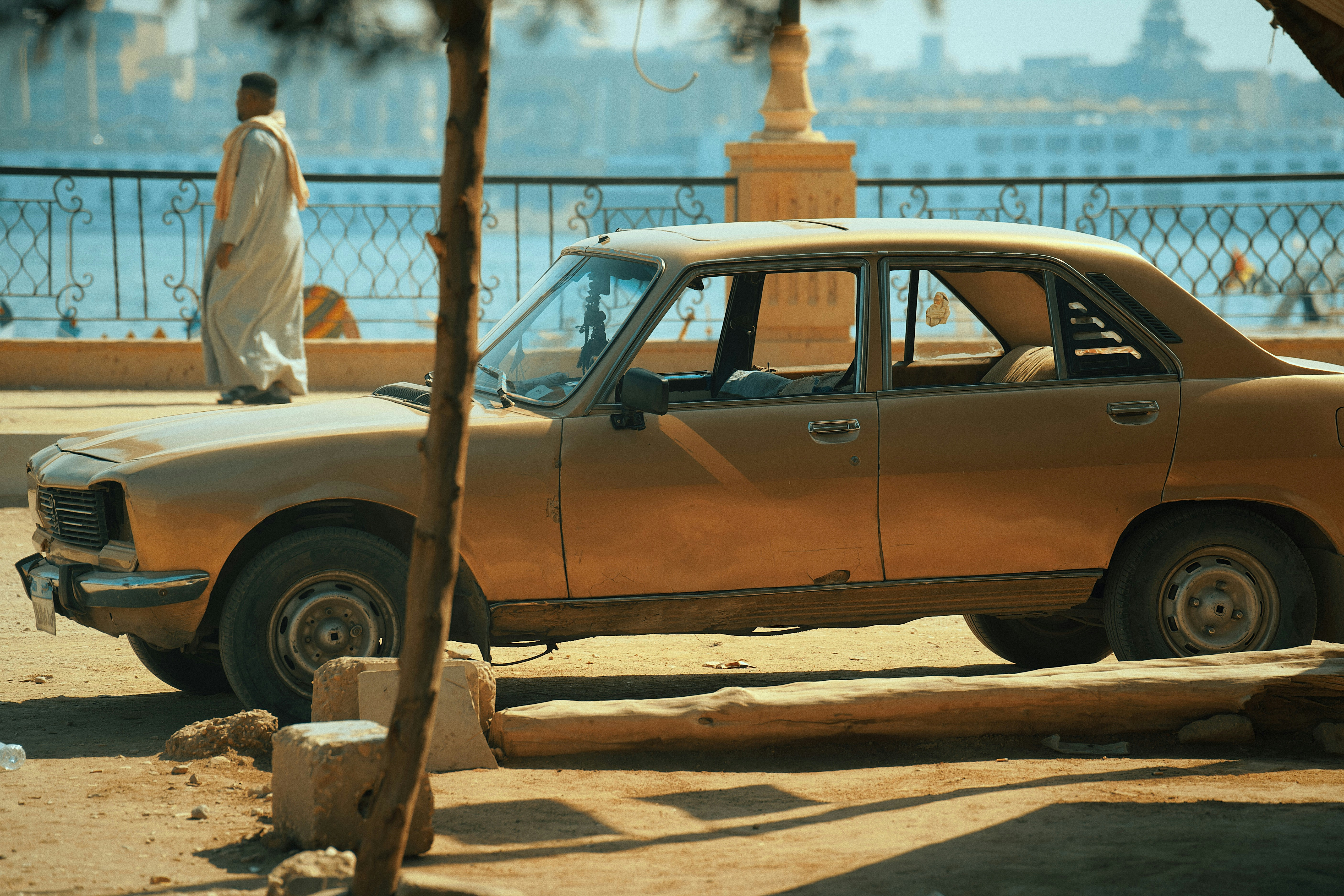 Sunlit relic: a golden sedan resting by the seaside promenade