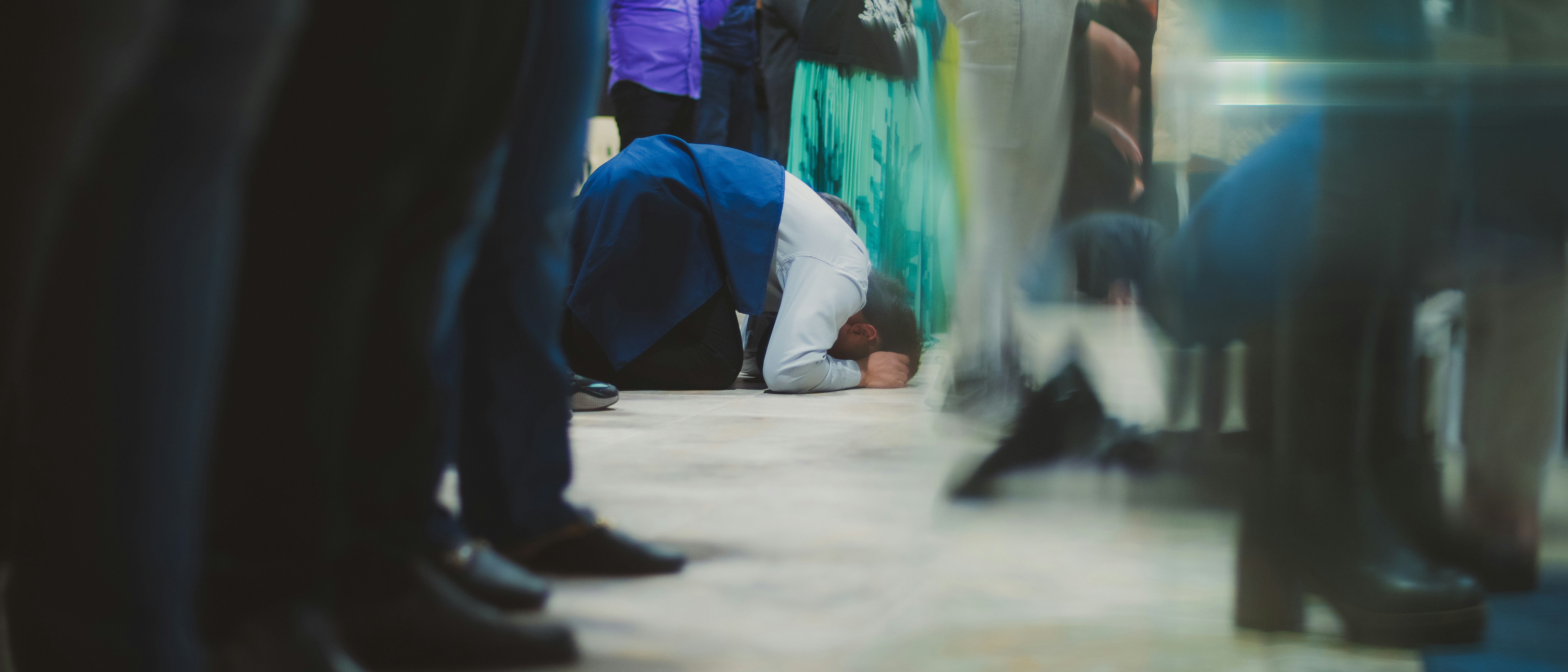 Collapsed Silence: A Kneeling Figure in a Crowded Corridor