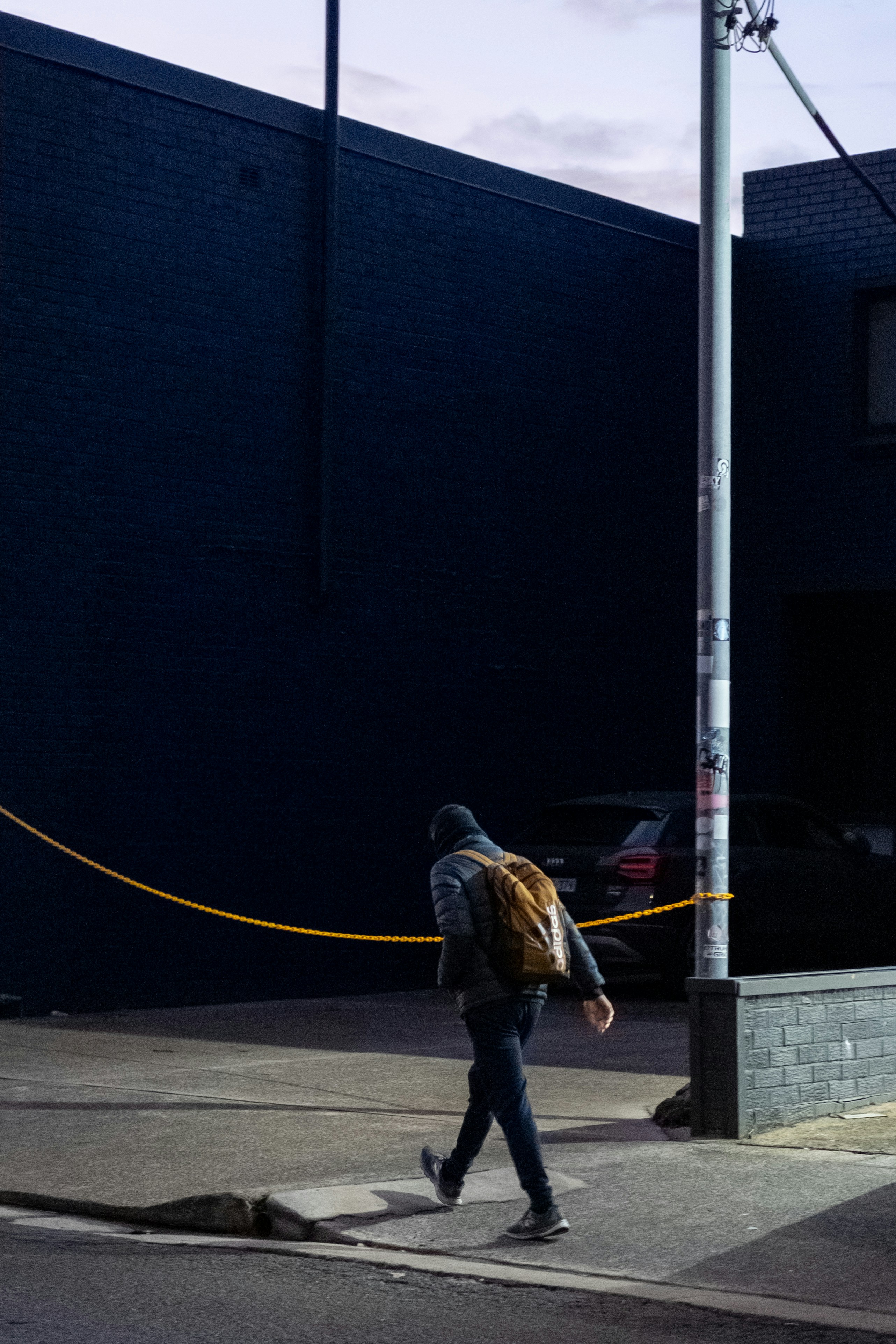 Urban Stroll at Dusk: A lone commuter under a weathered streetlight