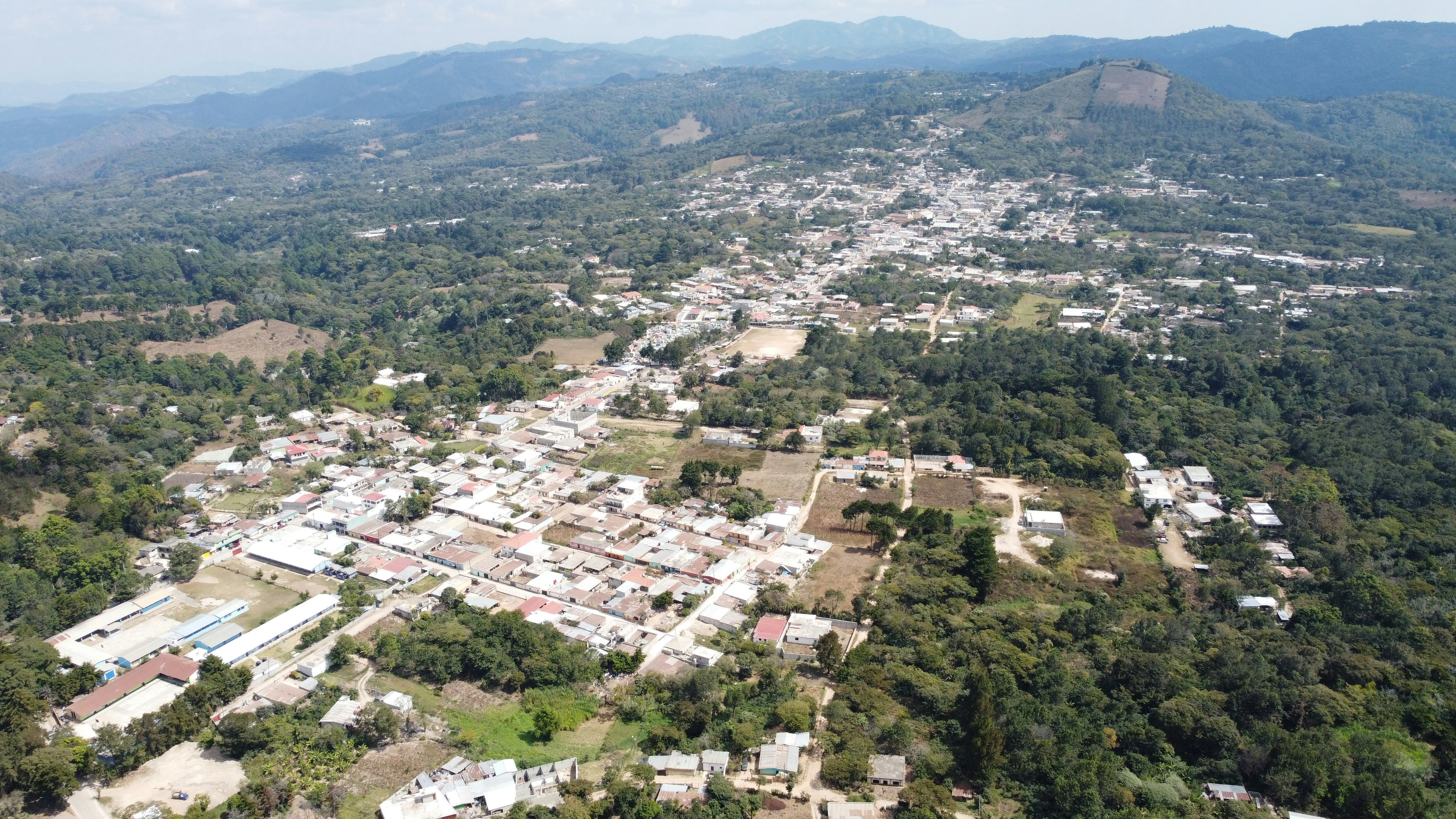 Aerial Tapestry: Suburban Grid Wends Through Verdant Valleys