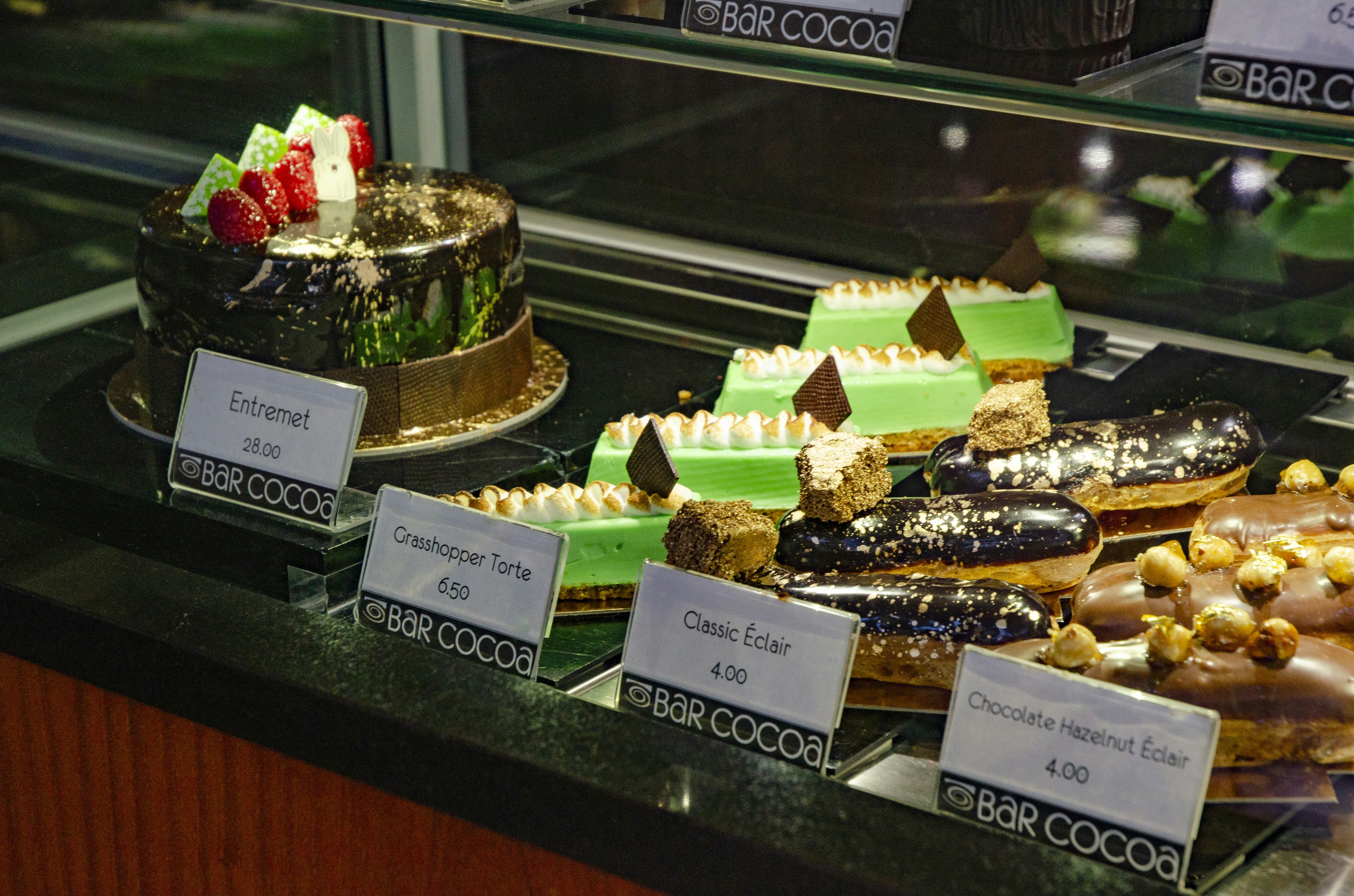 Miniature chocolate éclairs and parfaits glow in a glossy bakery display