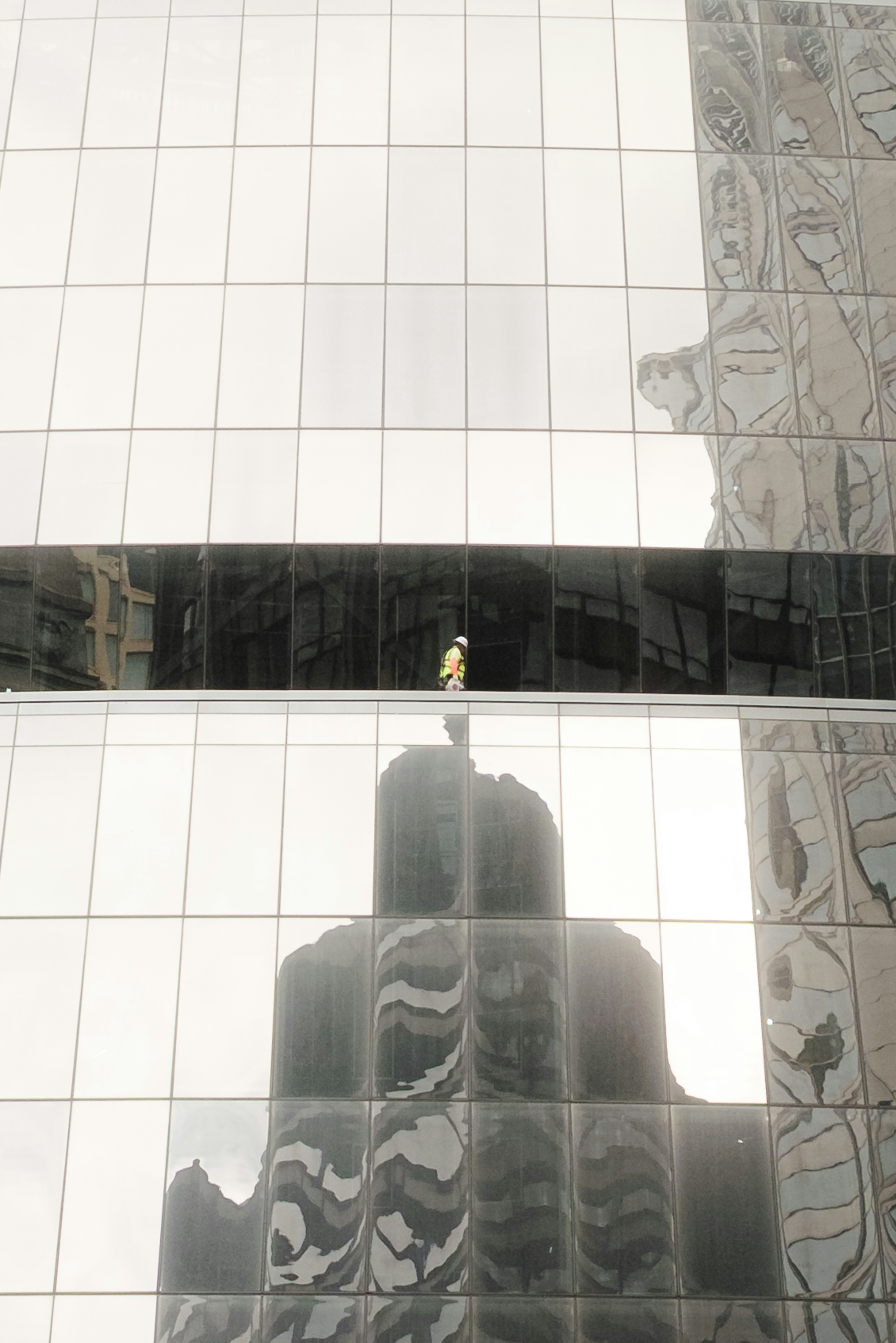Tiny Worker, Giant Glass: A Silhouette of Scale on a Shimmering Facade