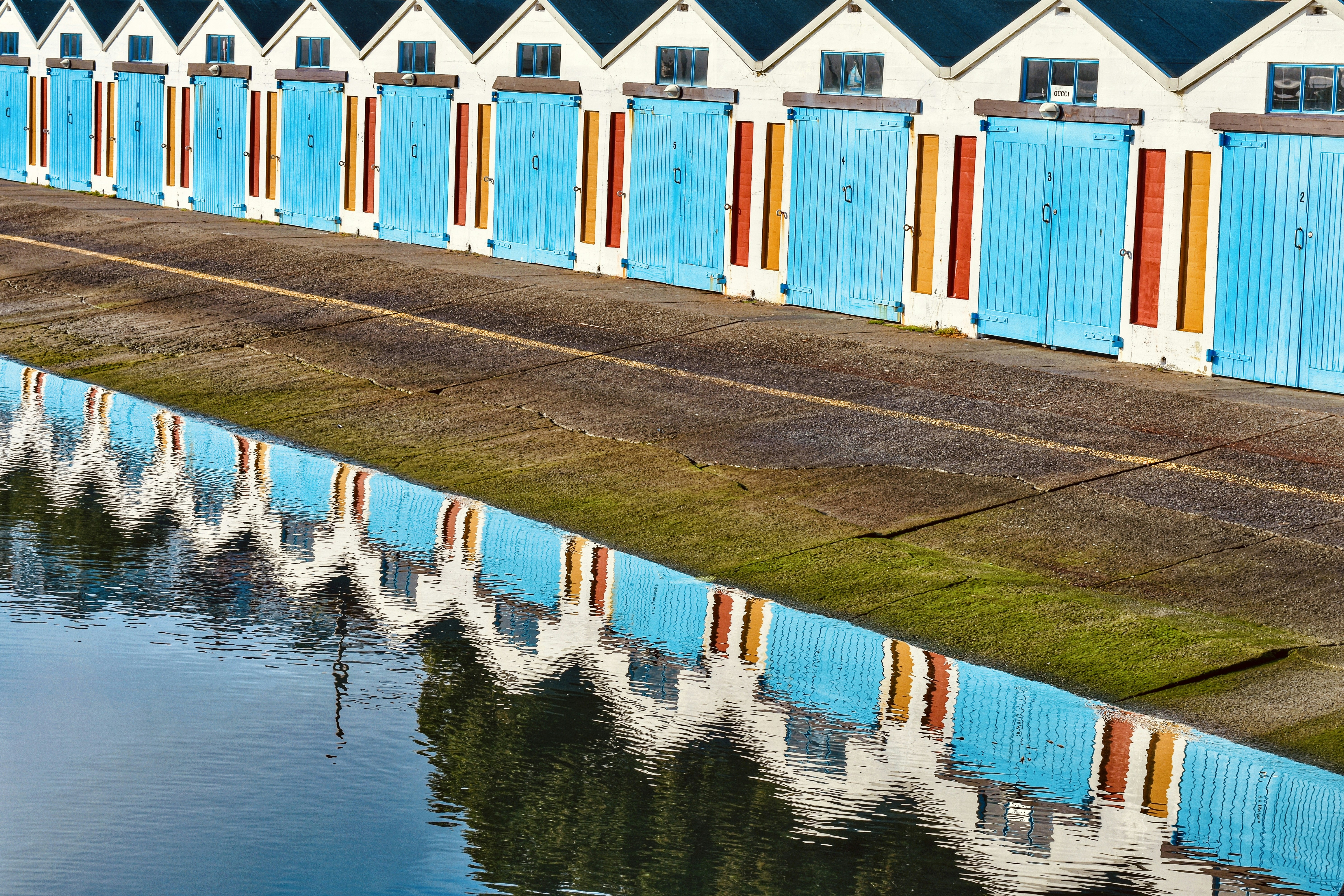 Row of Blue Doors Reflected in Calm Water at Sunrise