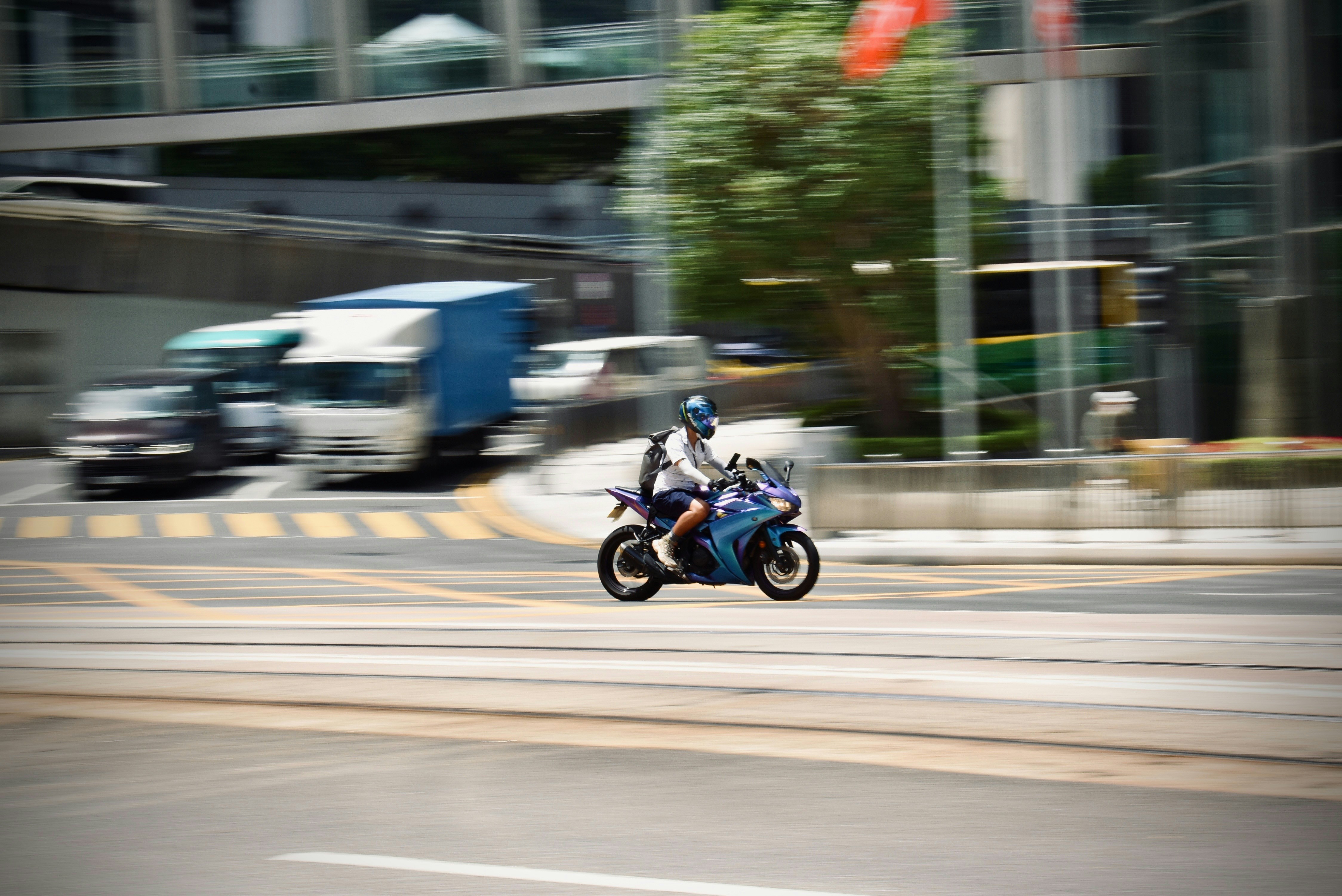 Motorcycle Rider in Motion Across an Urban Street