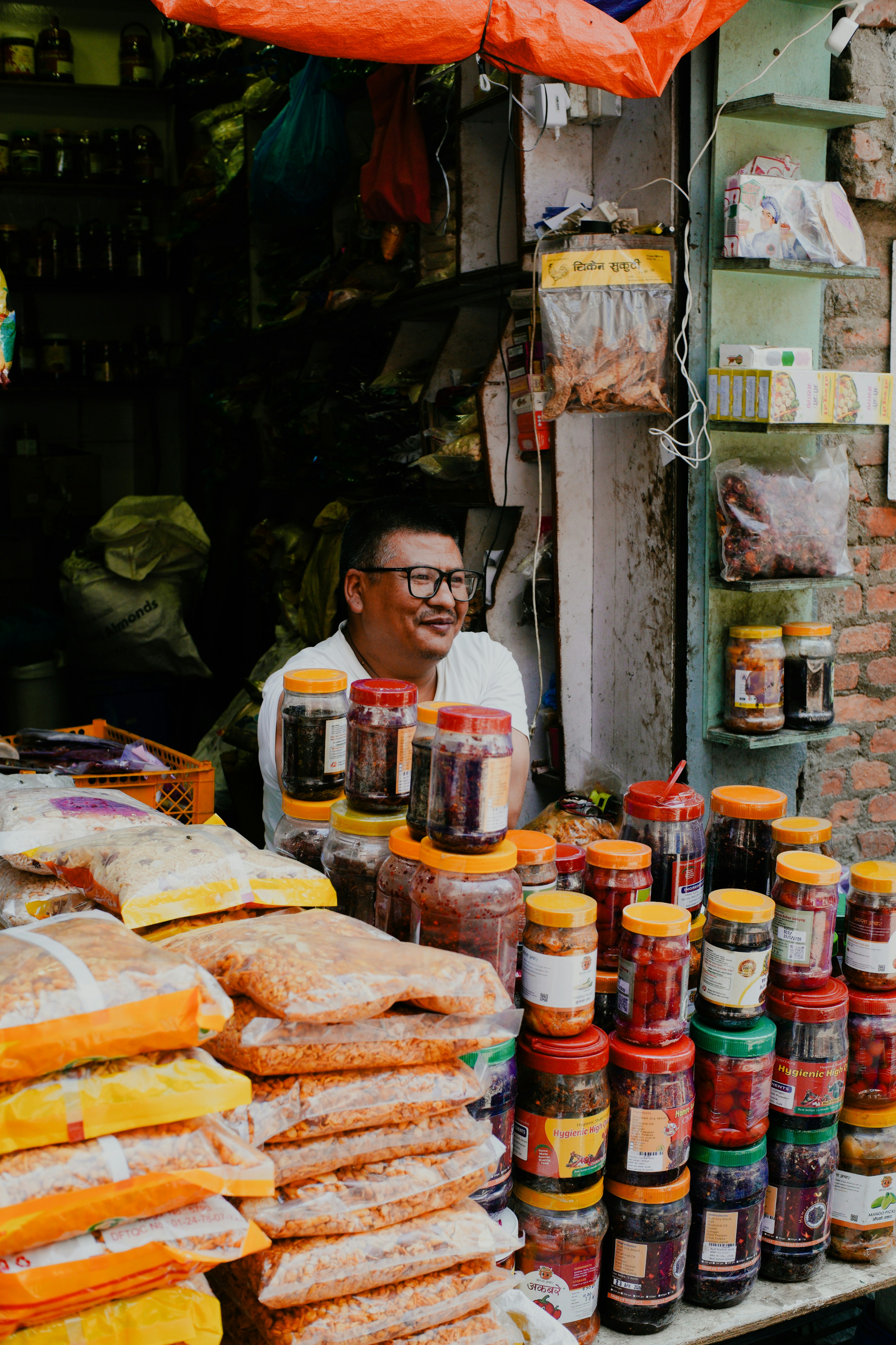 Smiling Vendor Amid Stacks of Spices and Jarred Condiments