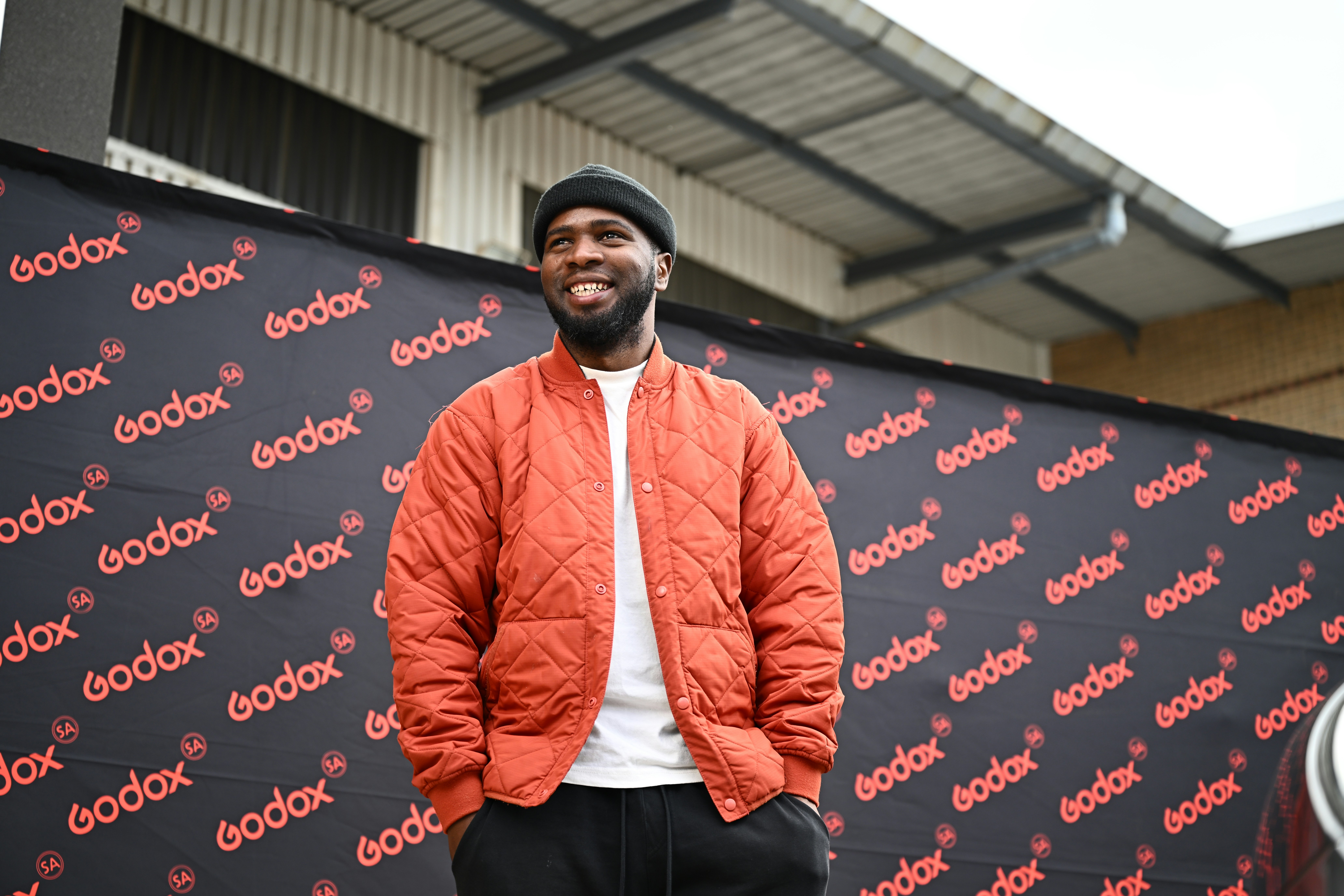 Bounce of Confidence: A Man in an Orange Jacket at a Brand Wall Event