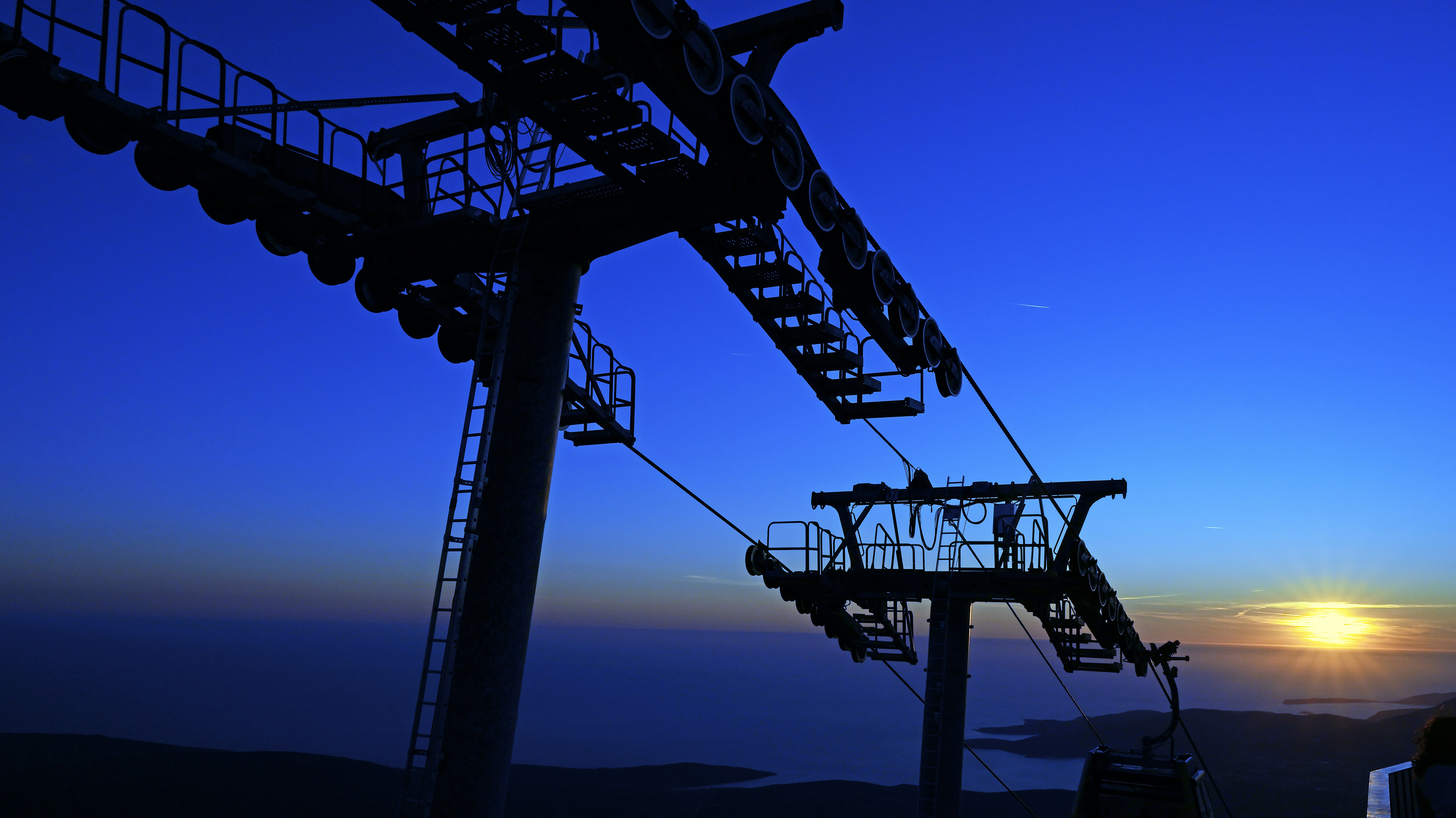 Sunlit Summit: Cable Car Towers Silhouetted at Dusk
