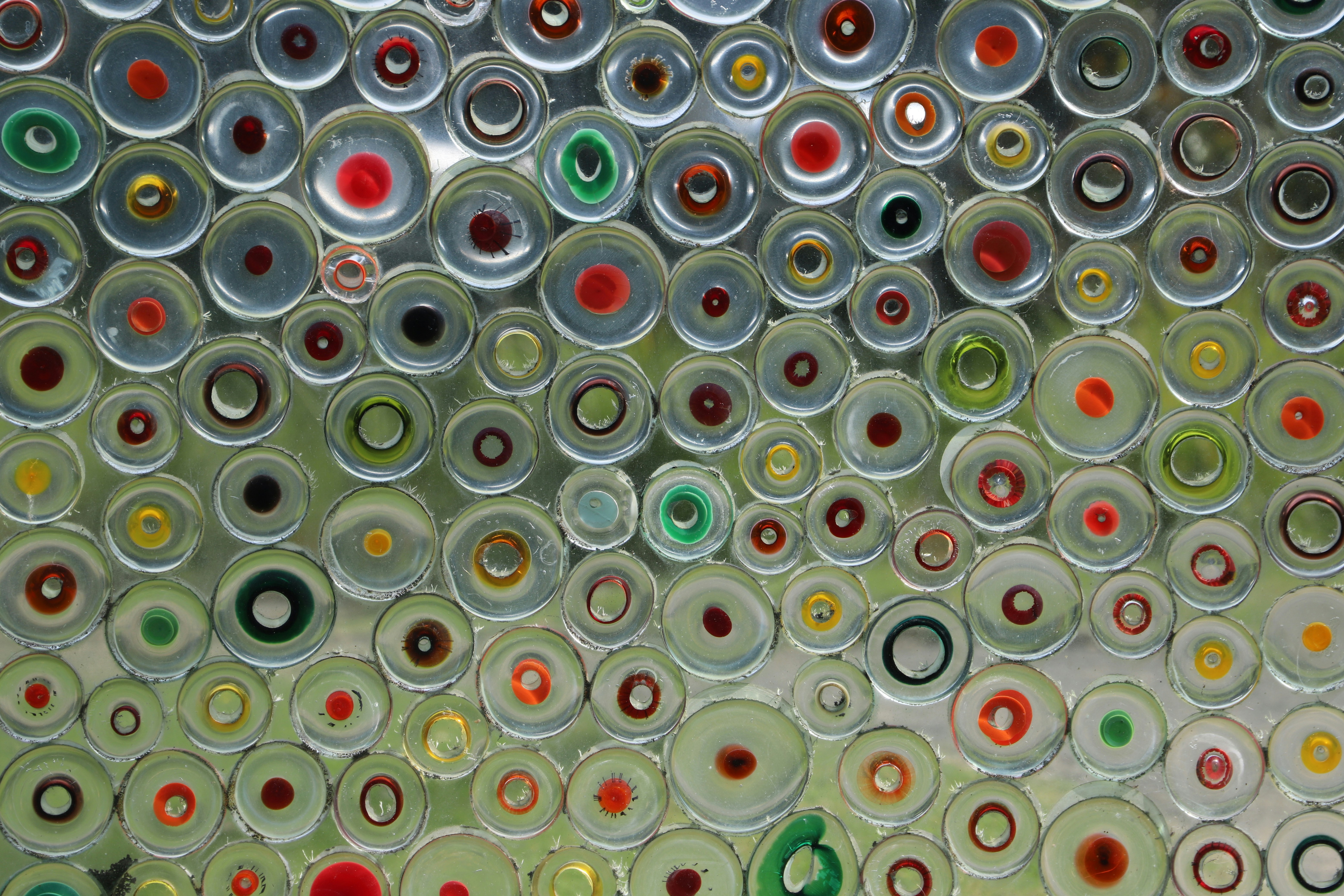 Close-up view of an array of circular lens-like tops with varied colors and centers, creating a dense, abstract mosaic texture.