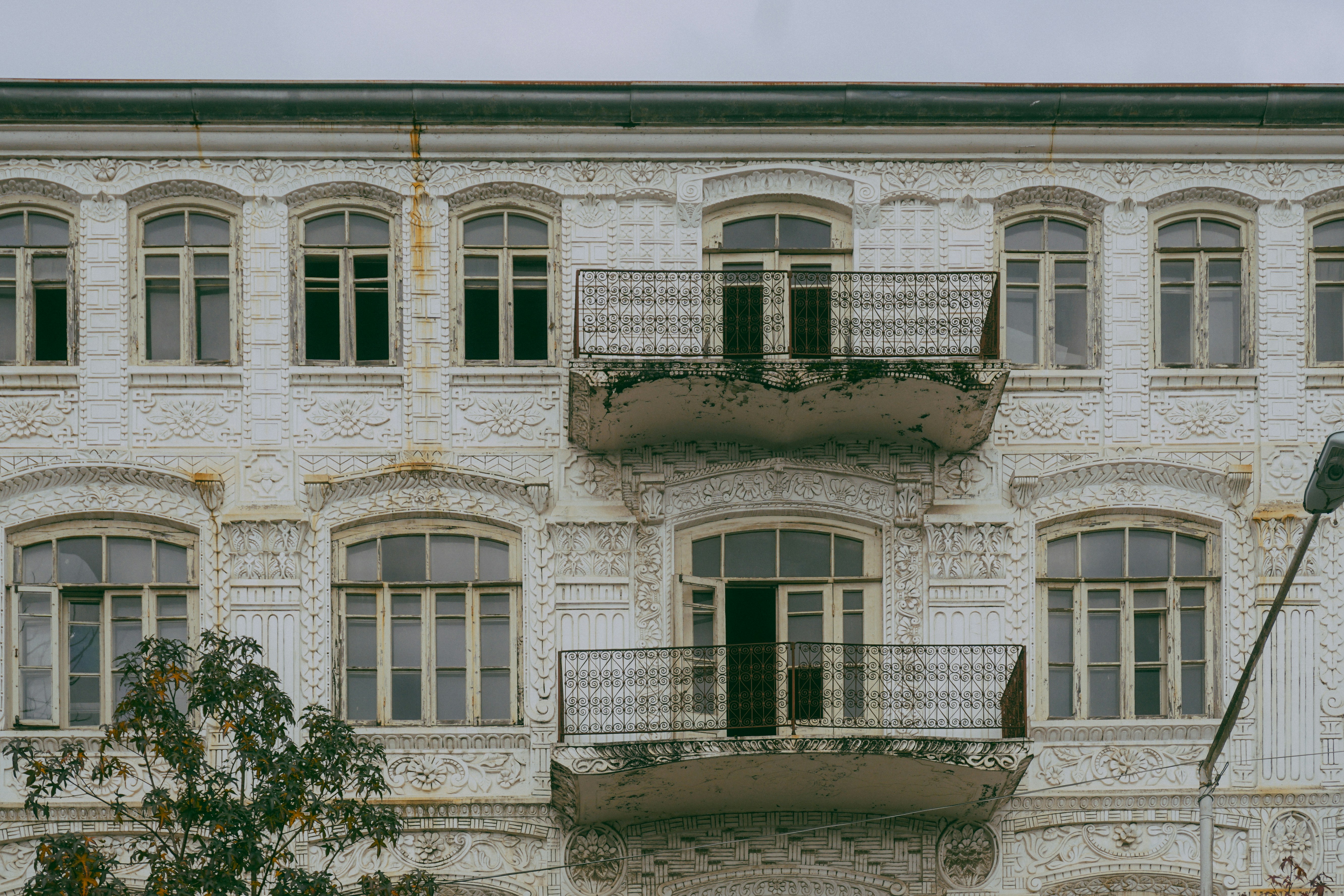 Cracked balconies and ornate brickwork on a sunlit courtyard façade