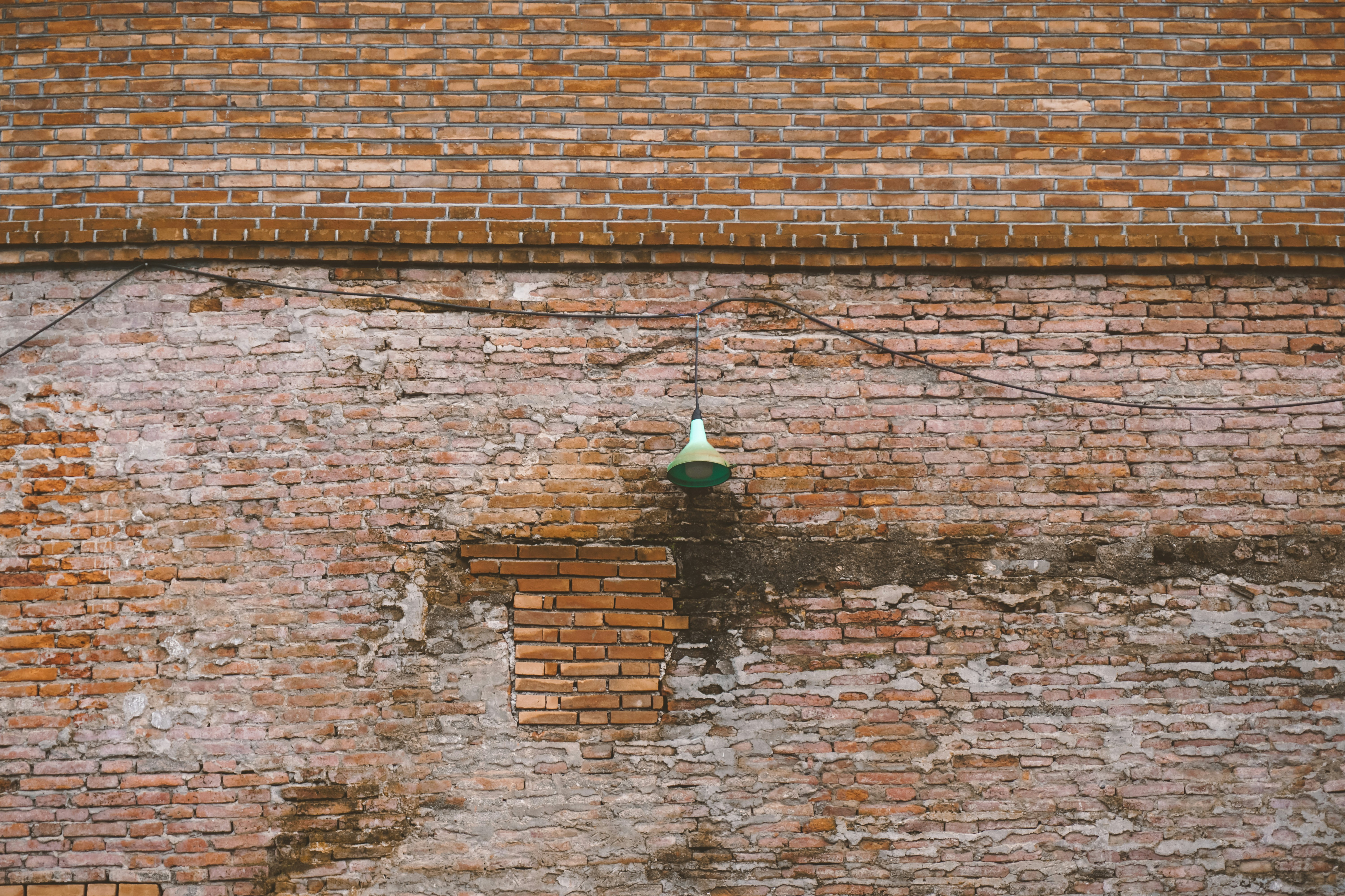 Aweathered brick facade with a solitary green lantern halo