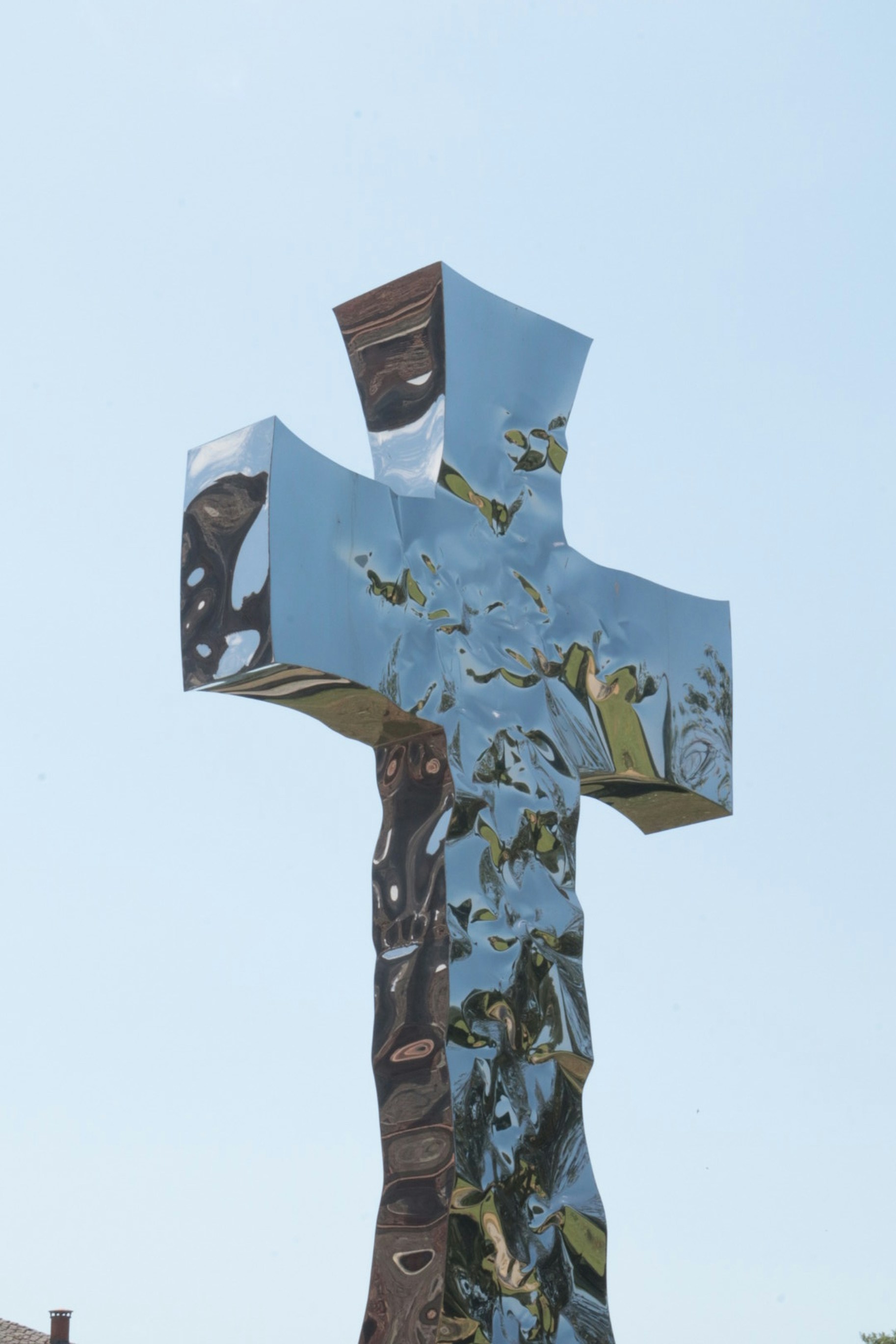 Shimmering Cross: A Metallic Sculpture Reaches for the Sky