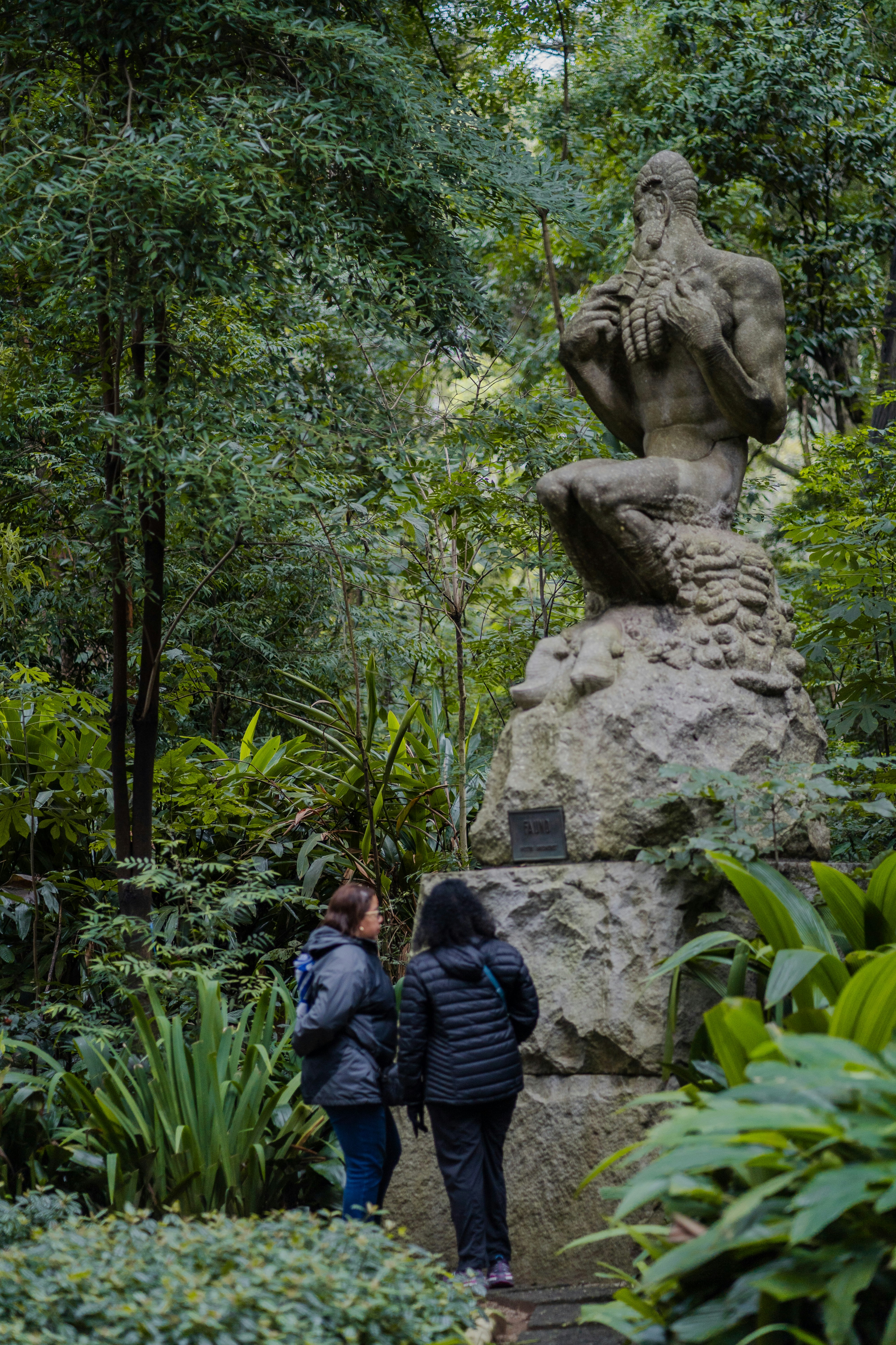 Quiet Reverie: Garden Statues Amid Dense Foliage
