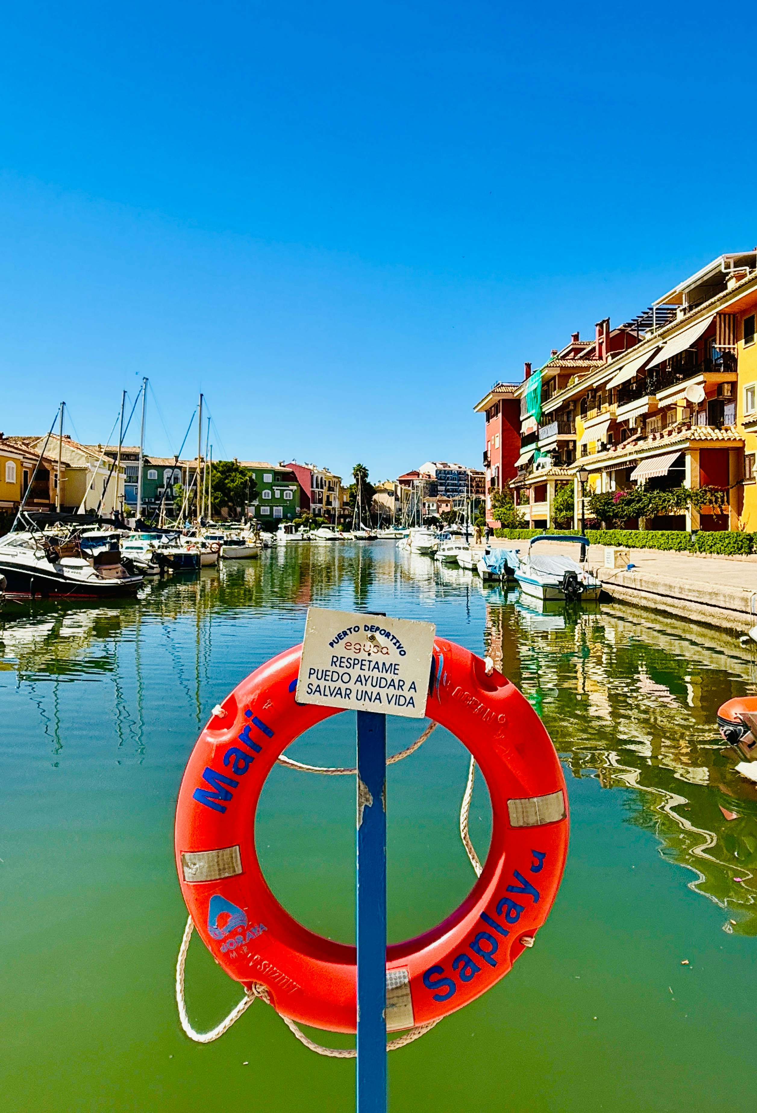 Red Lifebuoy Anchors a Colorful Canal Scene