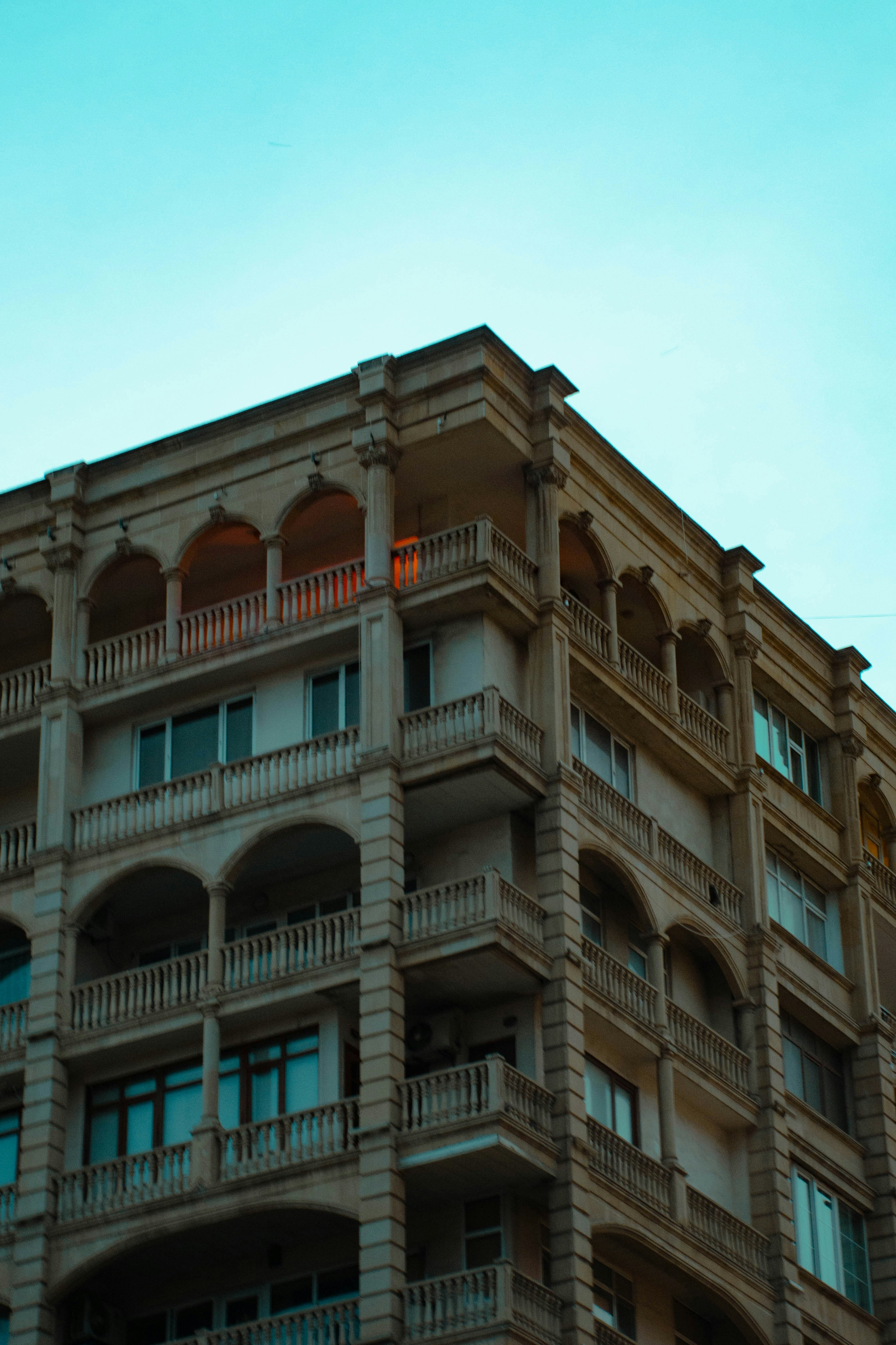 Cornered Heights: Balcony Arches Rising Above a Sunlit Facade