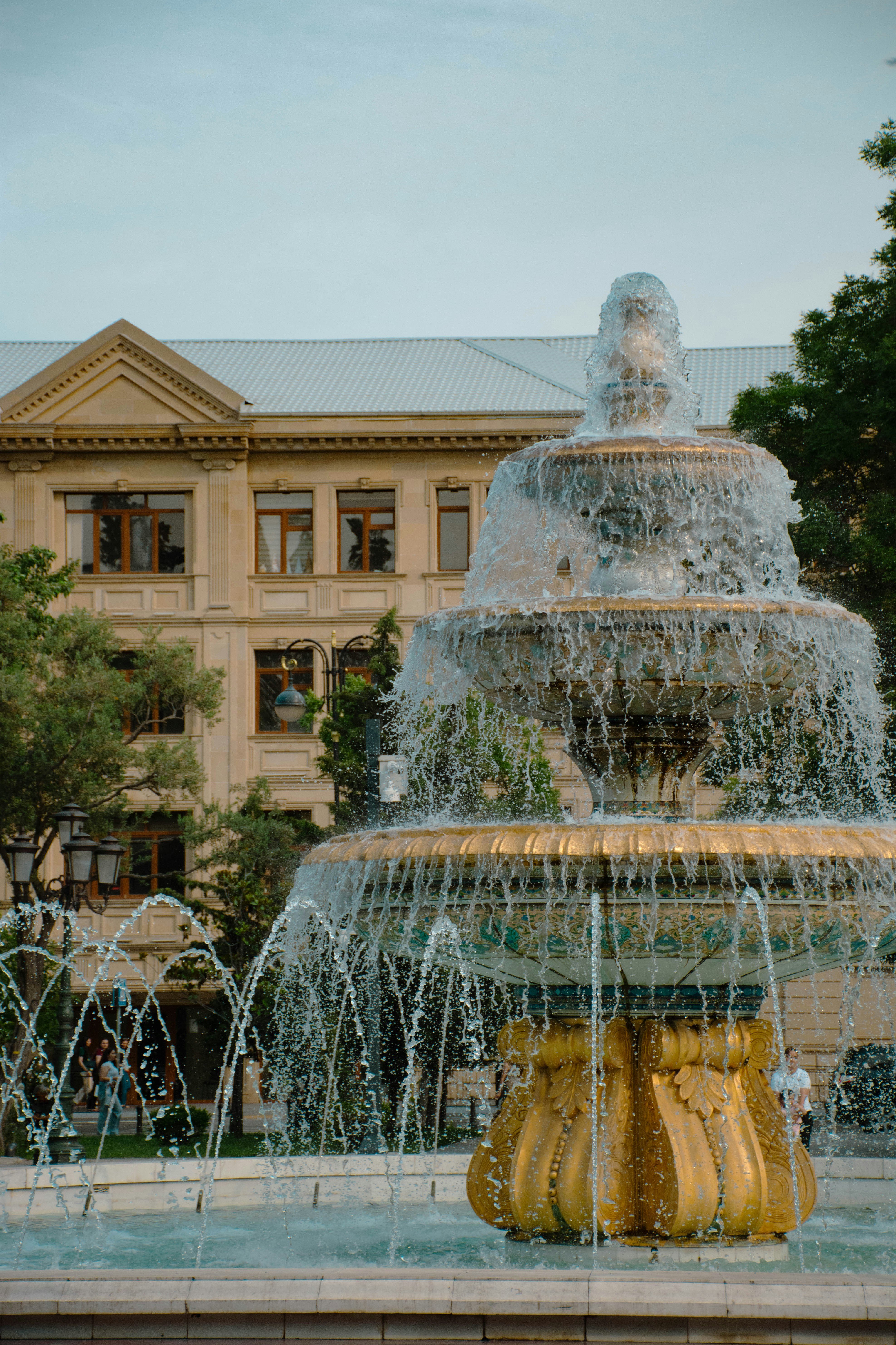 A multi-tiered fountain with golden accents in a city park