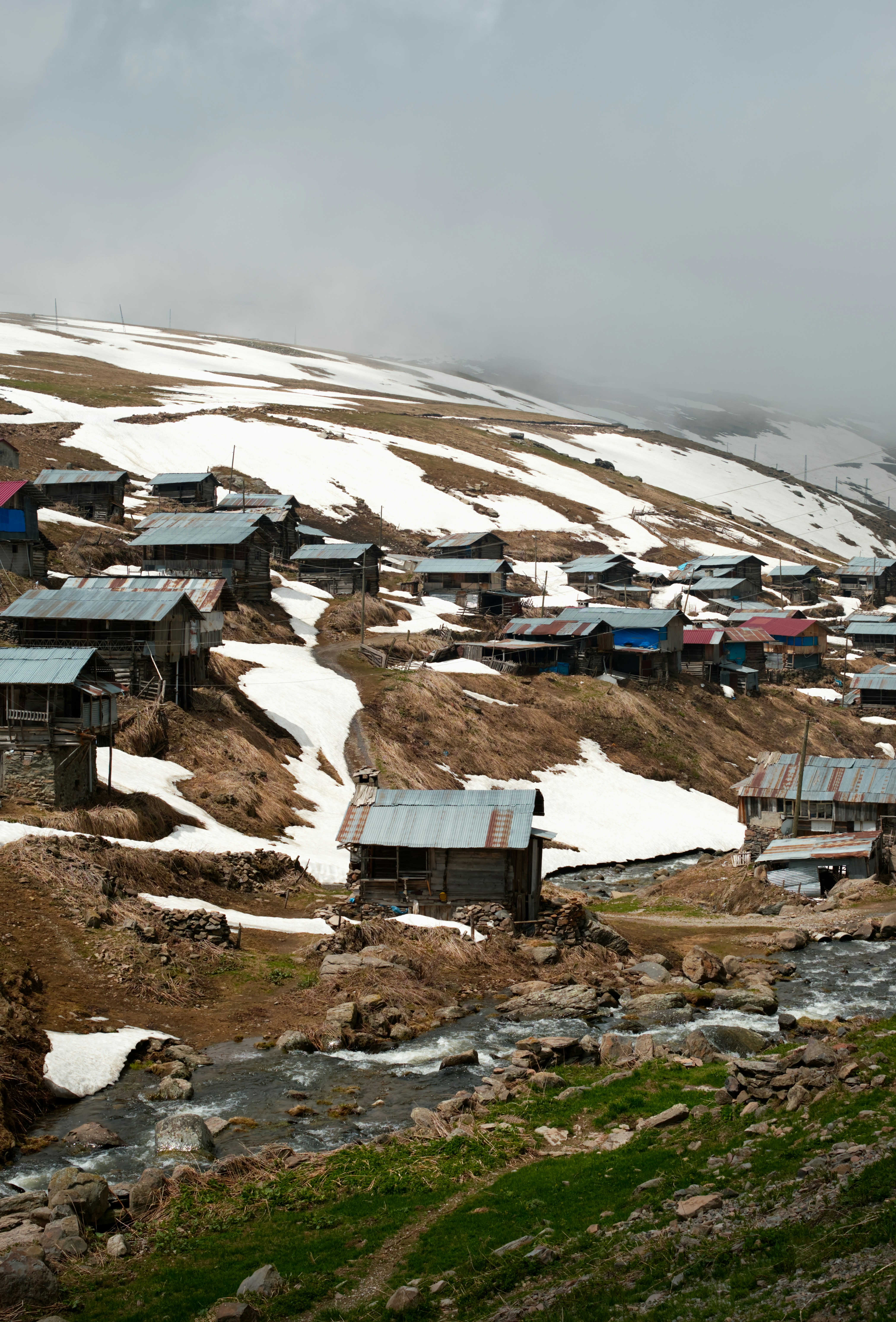 Snow-Clad Village Amid Rolling Terrain by a Mountain Stream