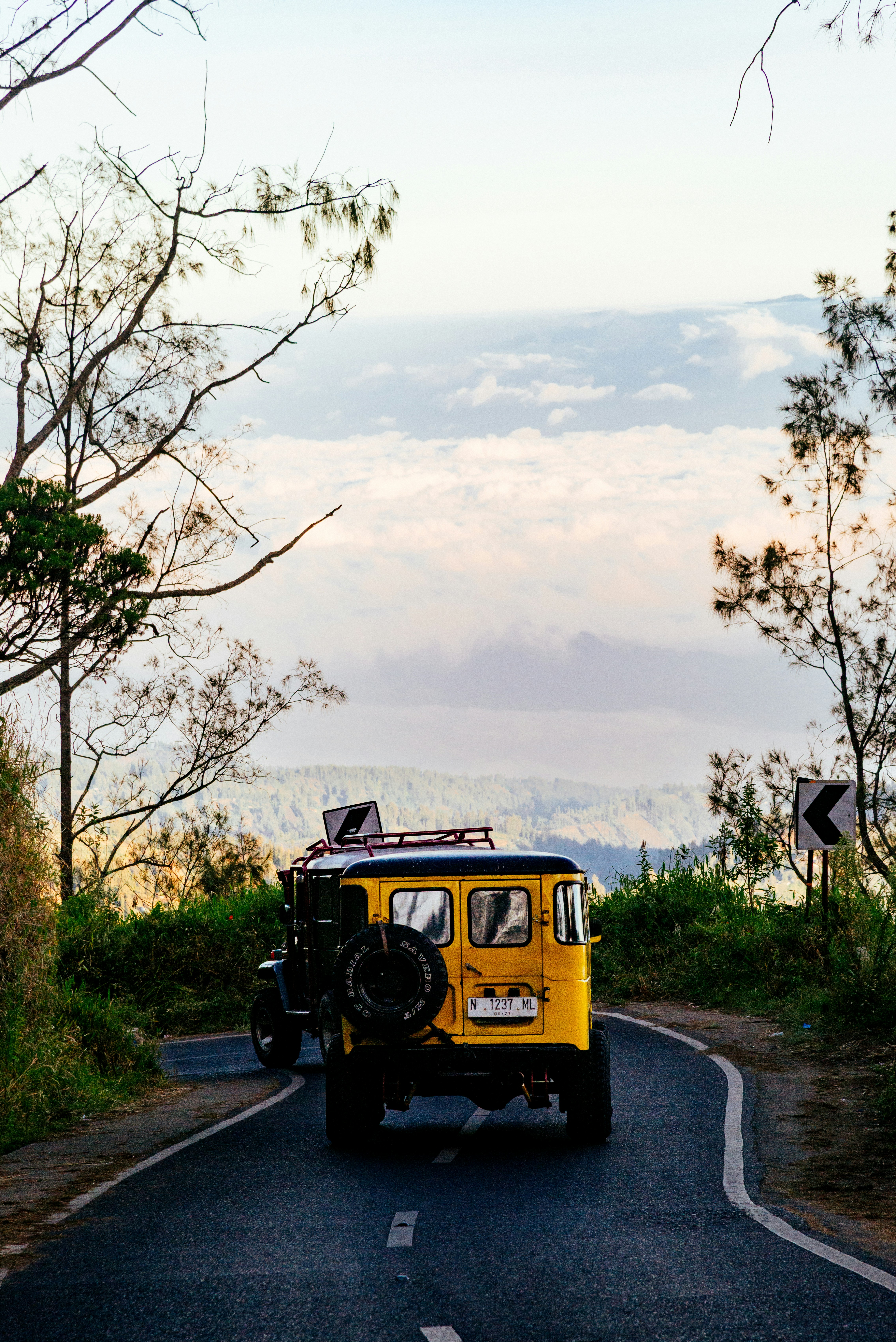 Yellow Jeep Navigates a Winding Mountain Road Toward the Mist